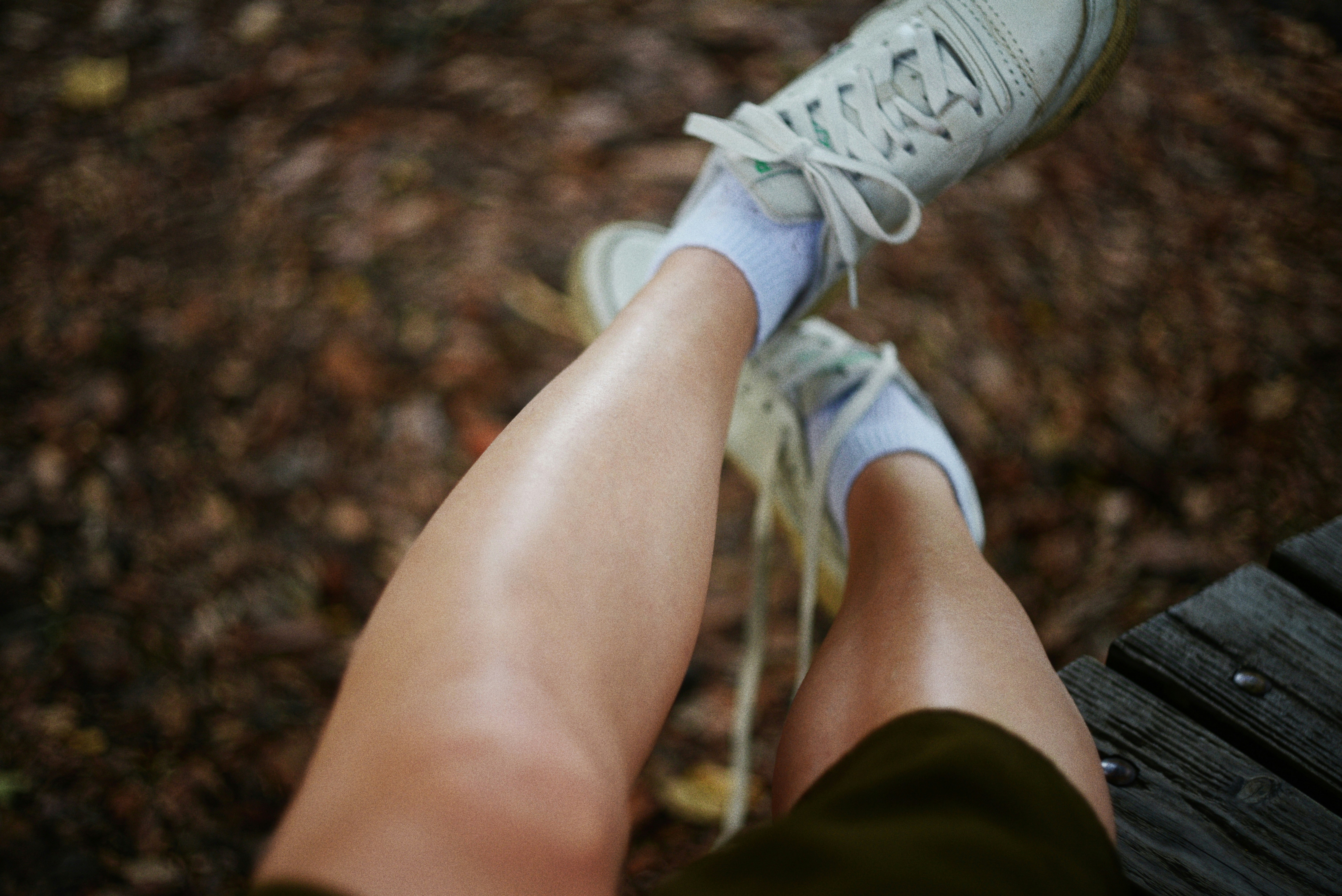 A Quiet Tread: Feet in sneakers Resting Over a Wooden Edge