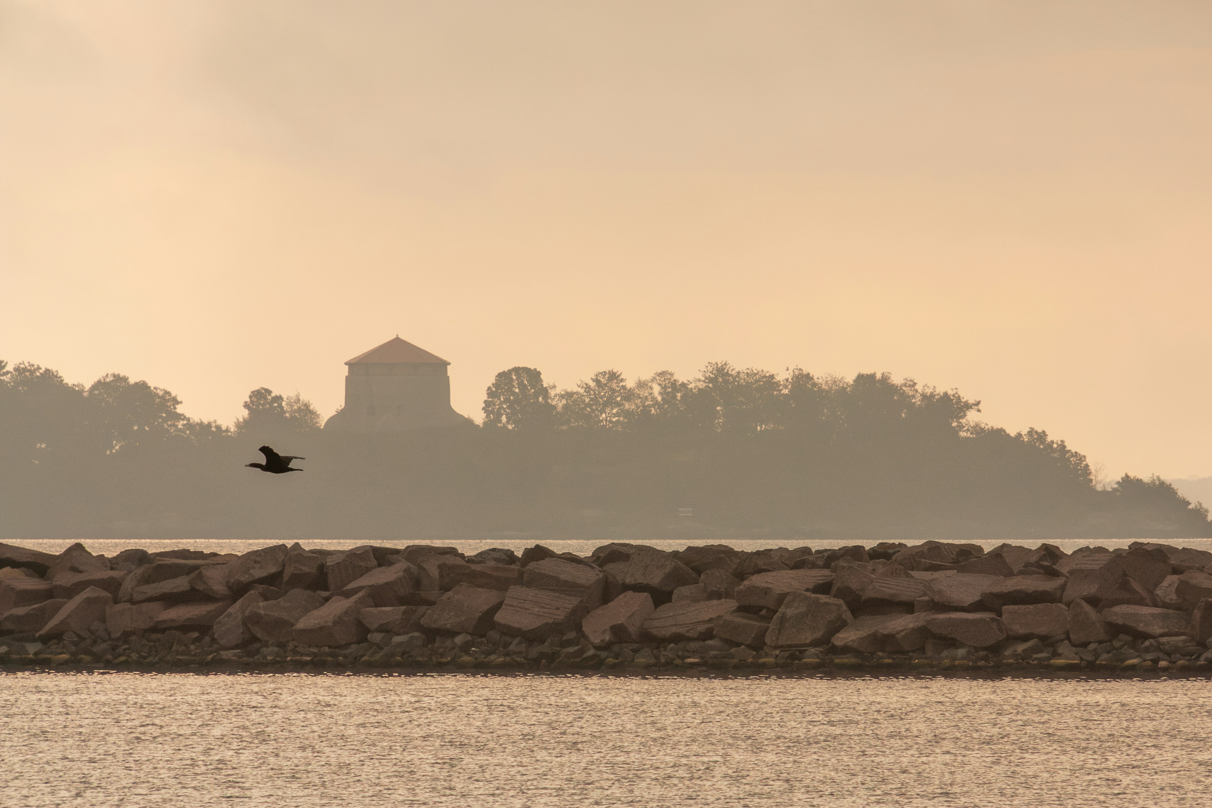 Silhouette over the Breakwater: A Distant Watchtower at Dusk