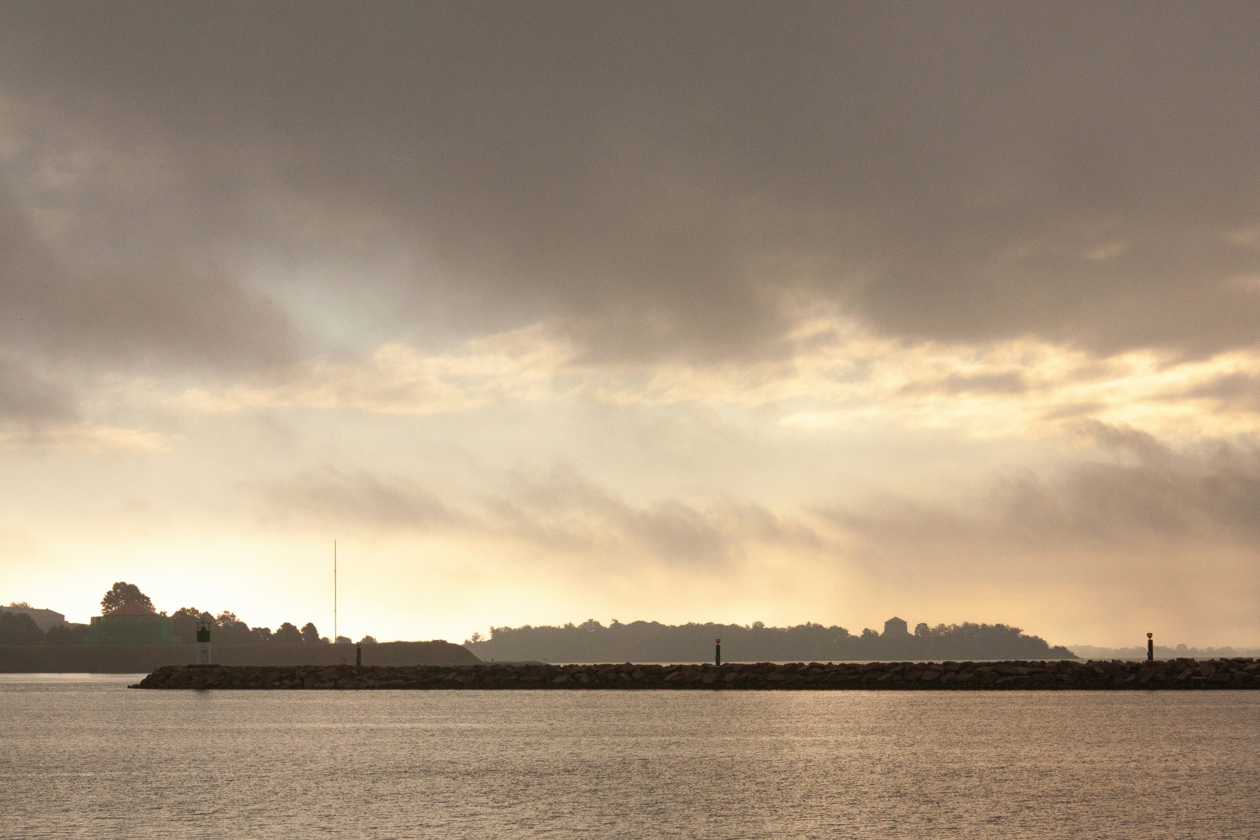 Dawn over a quiet harbor: a sunlit breakwater at rest