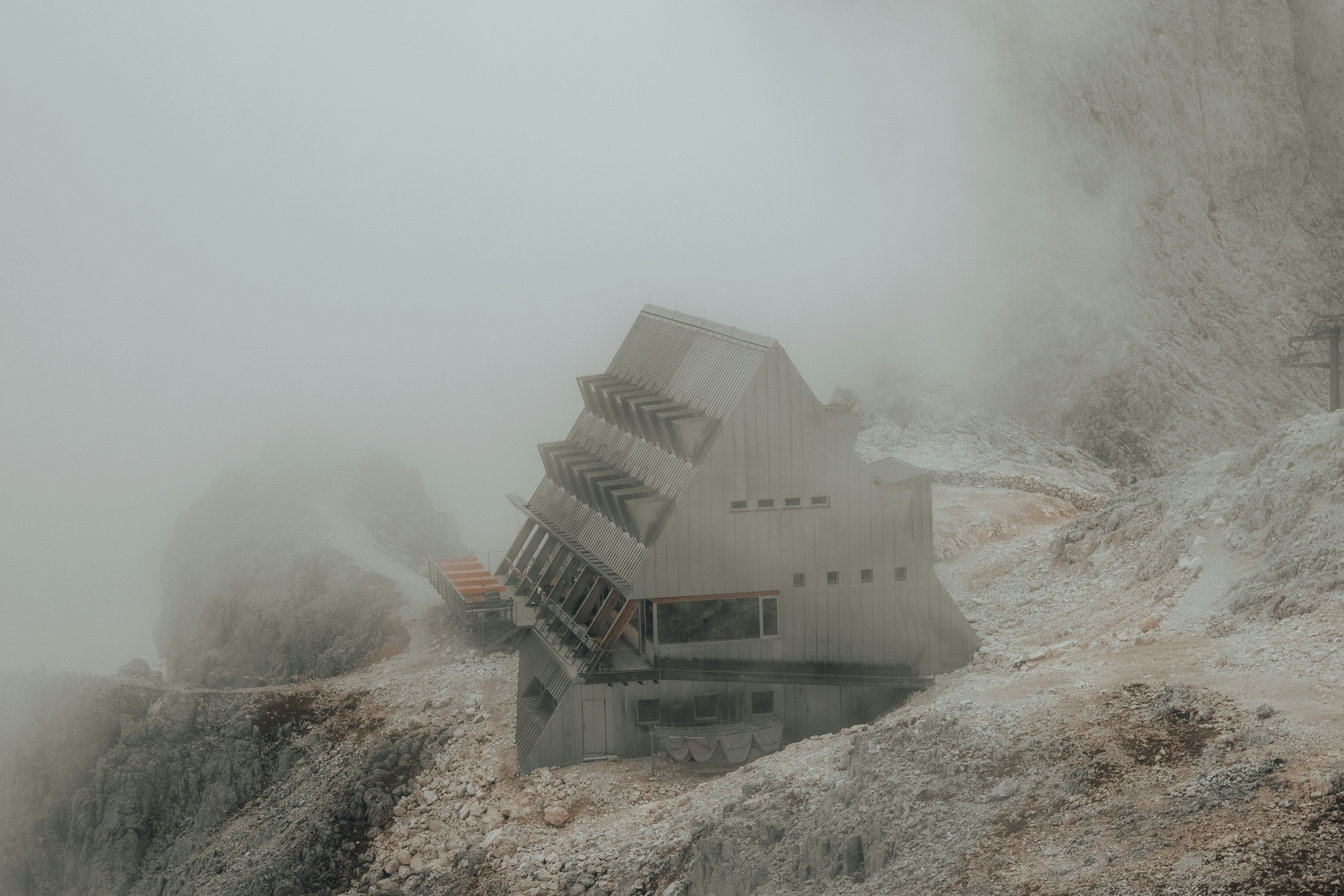 Concrete Refuge: A Crashed Structure Emerges from Mist on a Desolate Slope