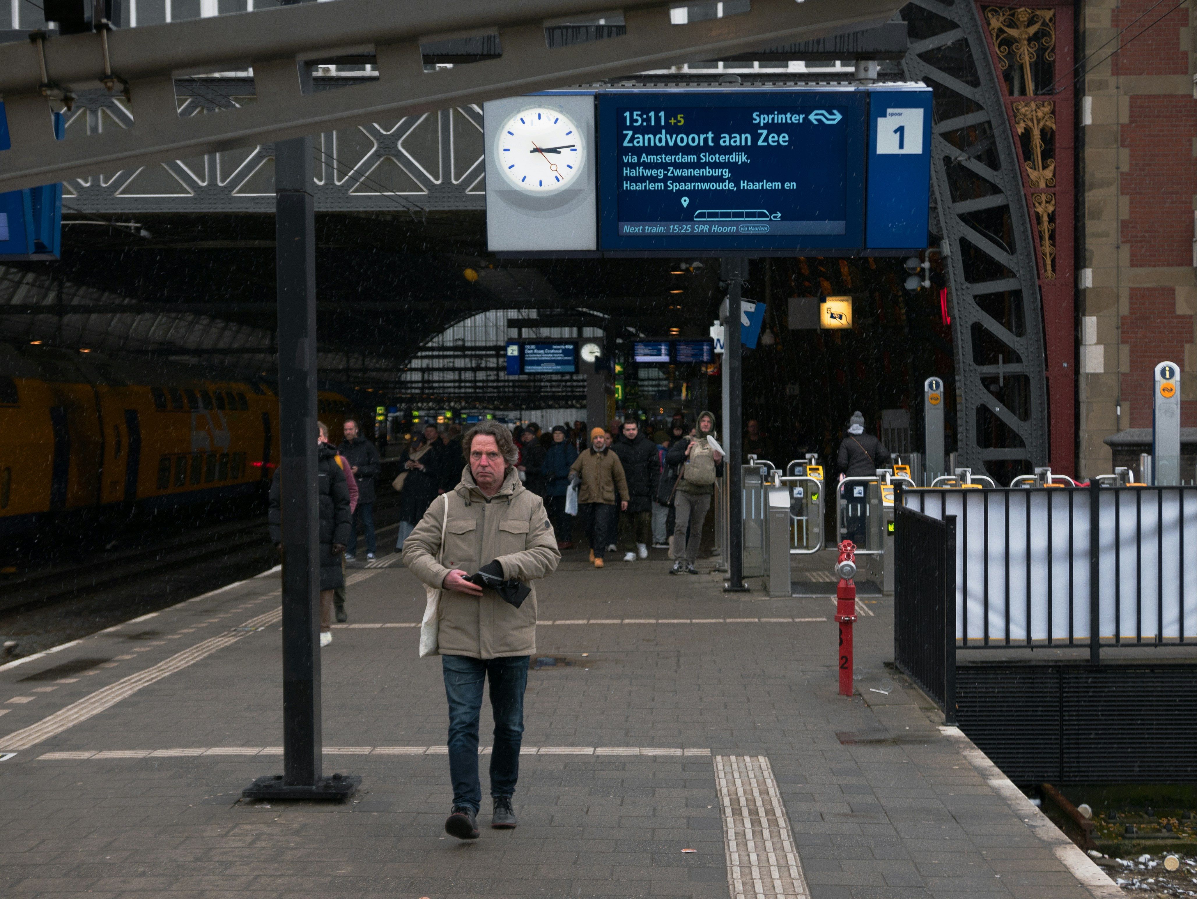 Platform Pulse: Commuter with a Camera Amidst a Busy Dutch Station