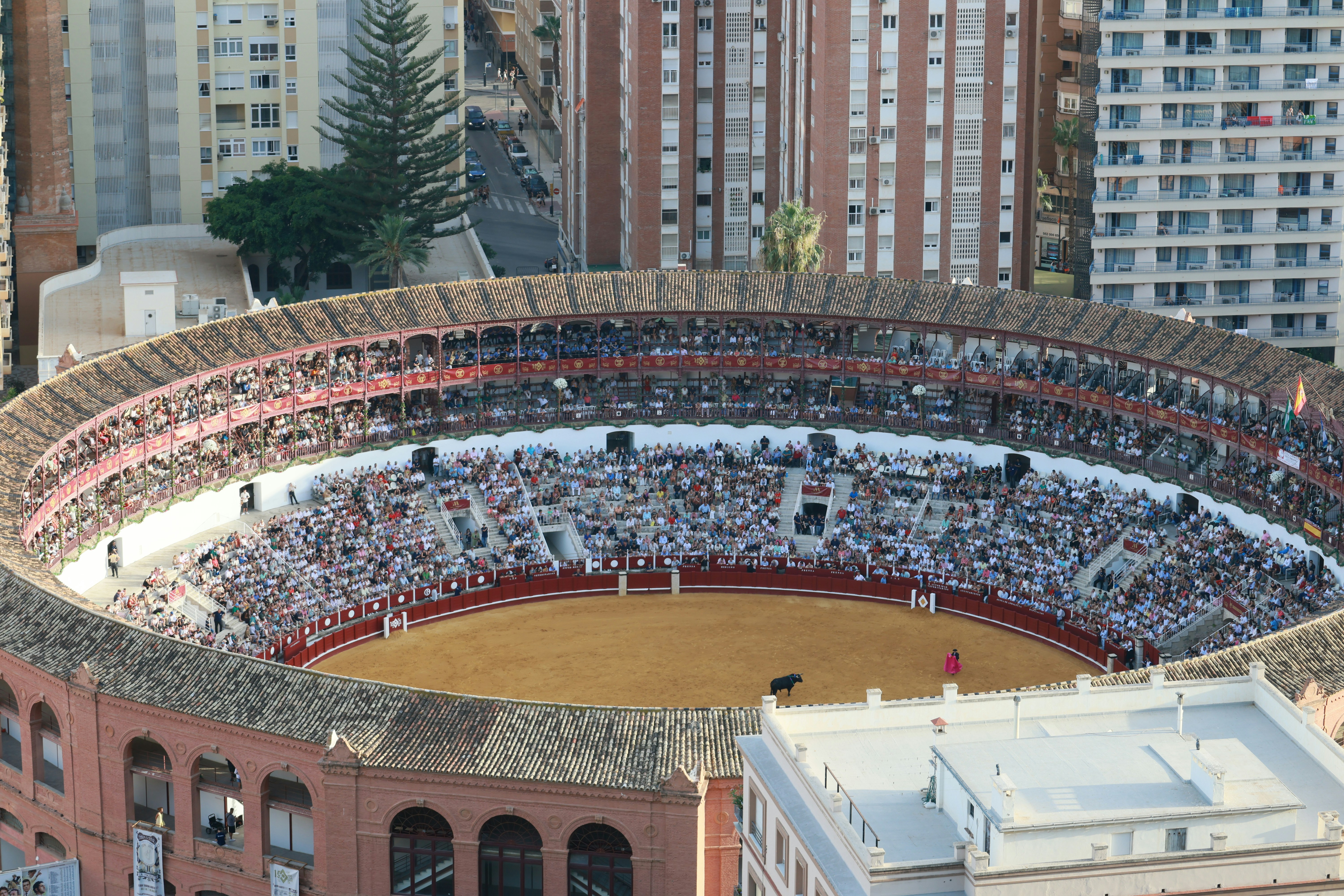 Aerial Arena: Sunlit Spain’s Circular Bullring Embraced by Urban Towers