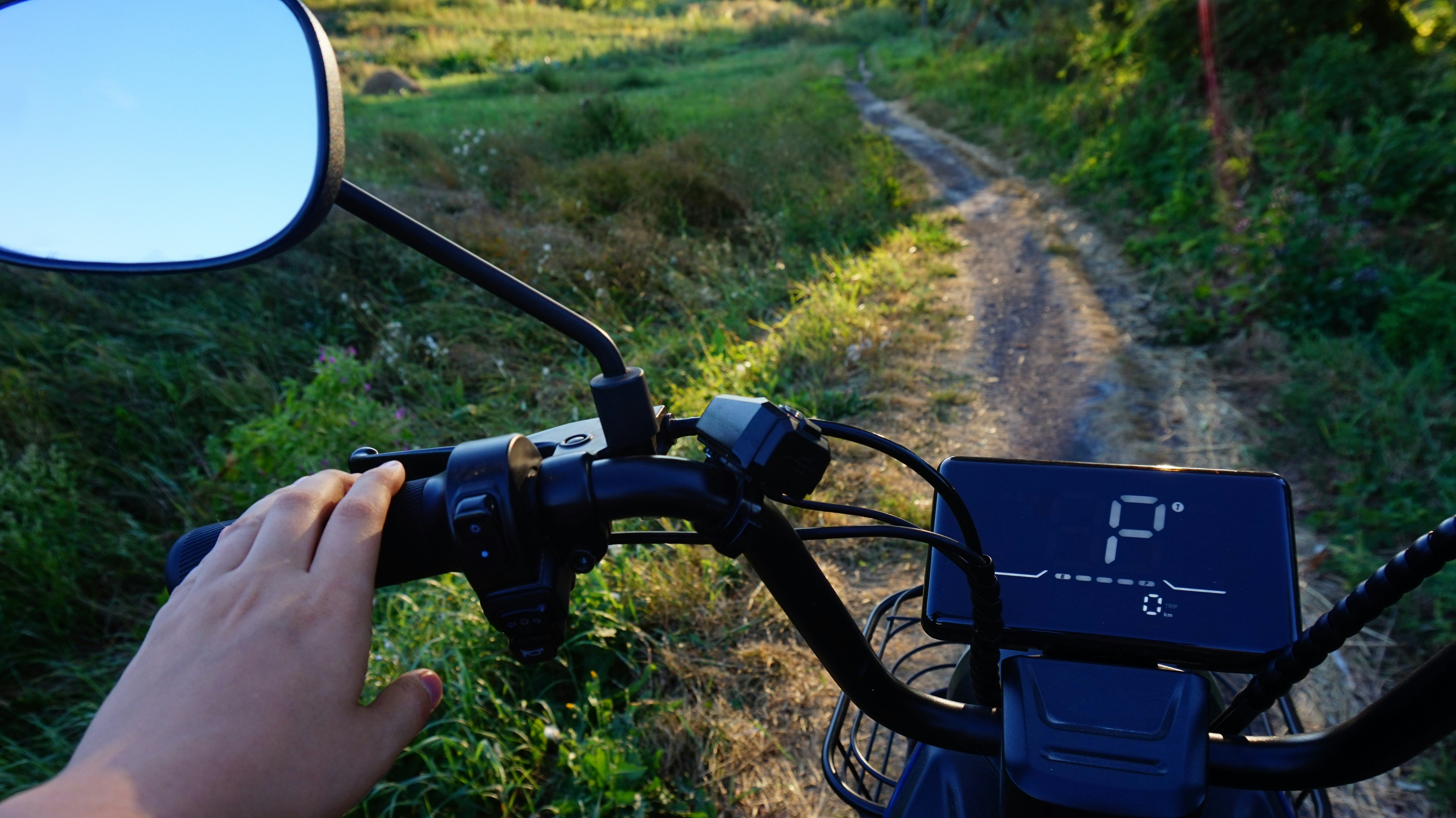 Rugged Ride: A Hand Grips the Bar as a Narrow Trail Winds Ahead