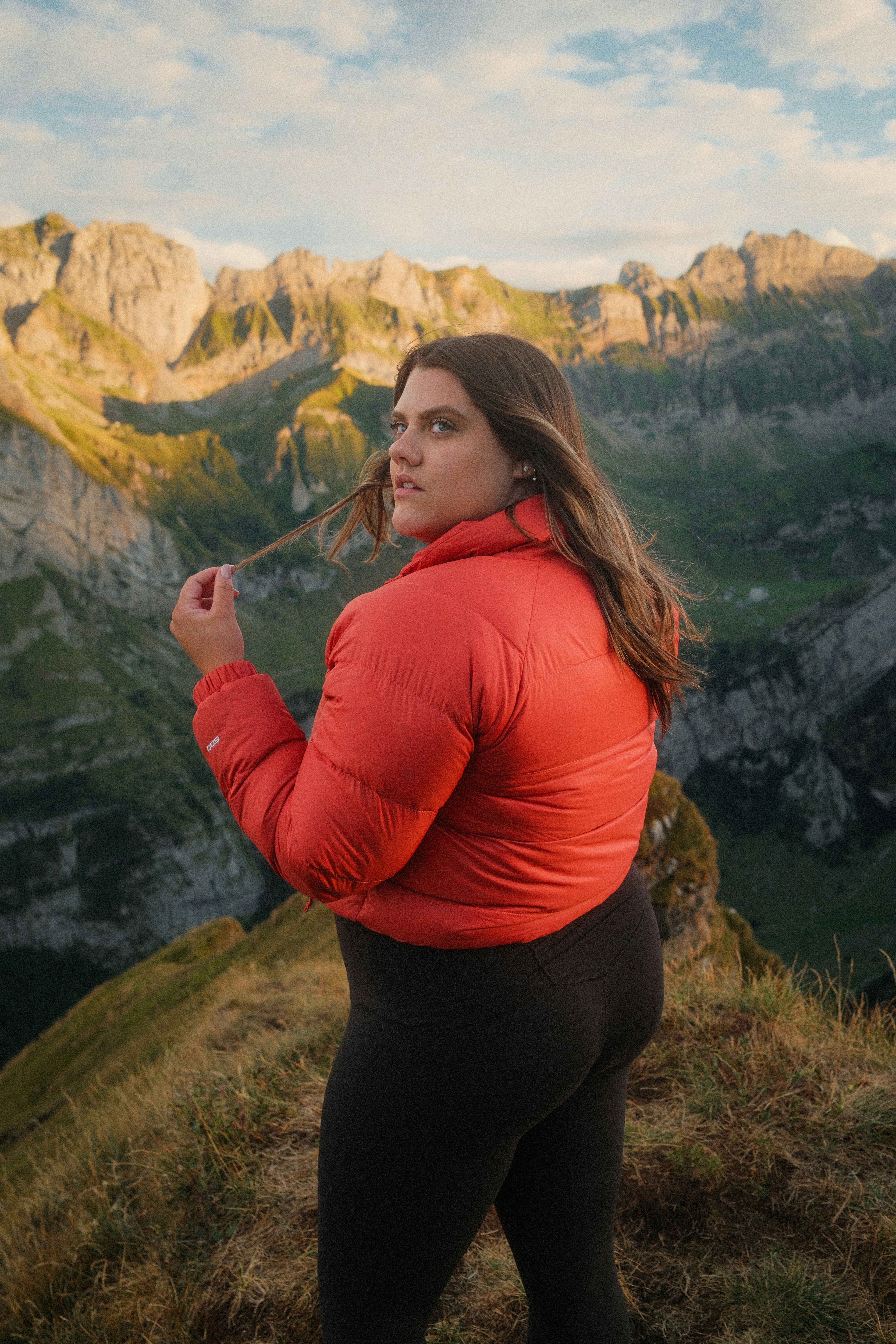 Red Summit Confidence: A Winter Jacket Portrait Against Alpine Escarpment