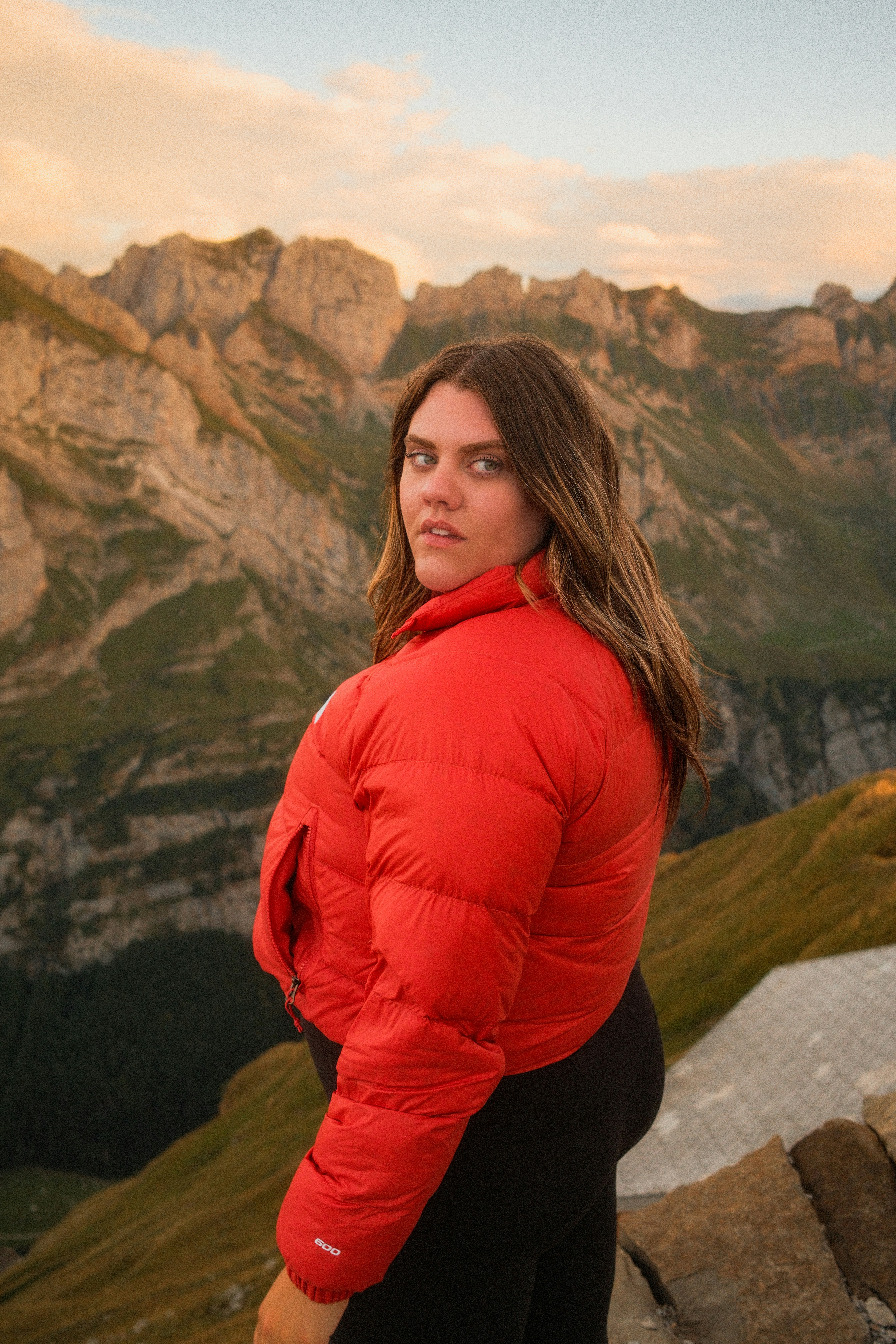 Red jacket, rugged peaks: a portrait against alpine cliffs at golden hour