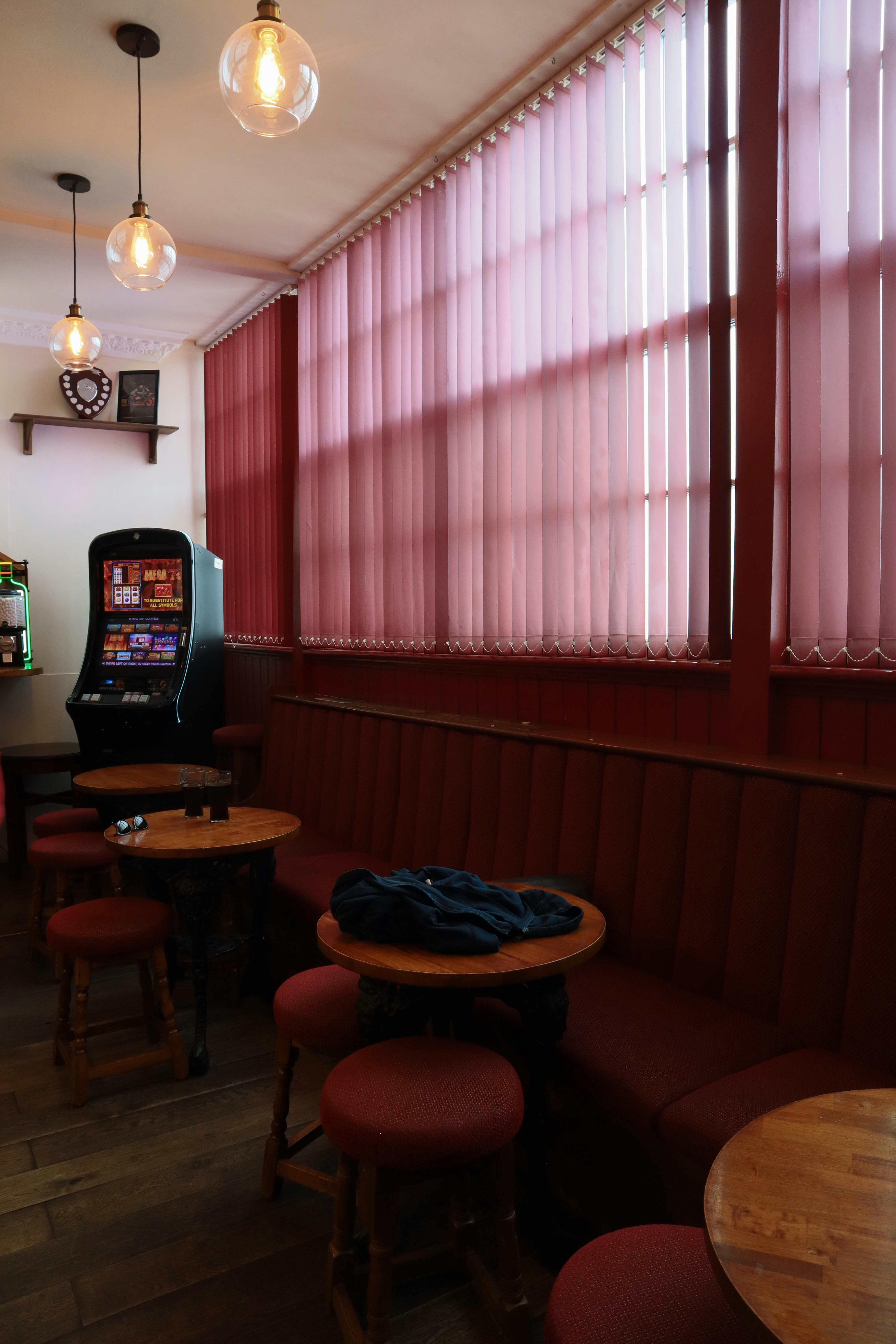 Muted Red Alcove: A Quiet Corner with a Slot Machine and Velvet Stools