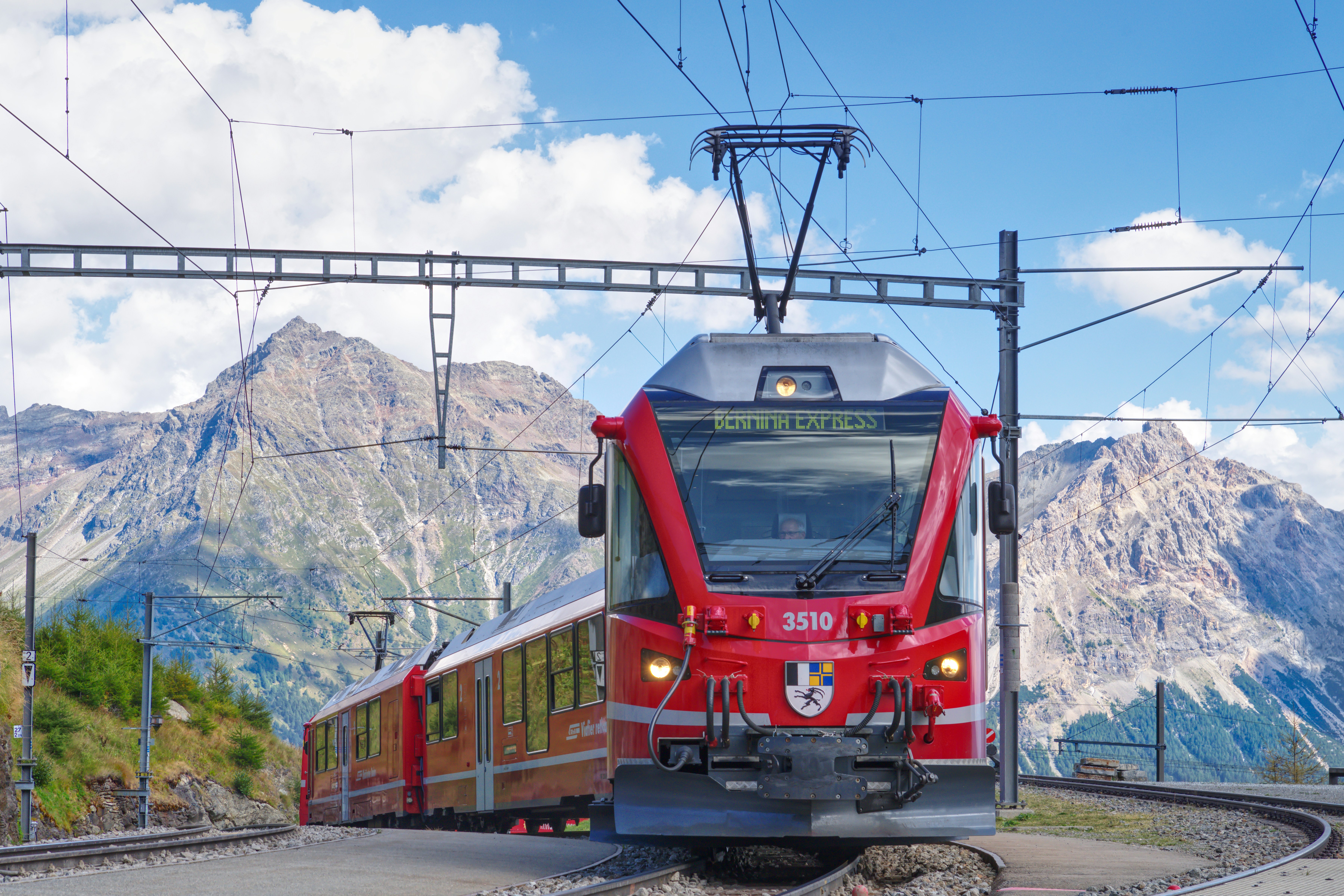 Red Locomotive Carving Through Alpine Tracks at Dusk