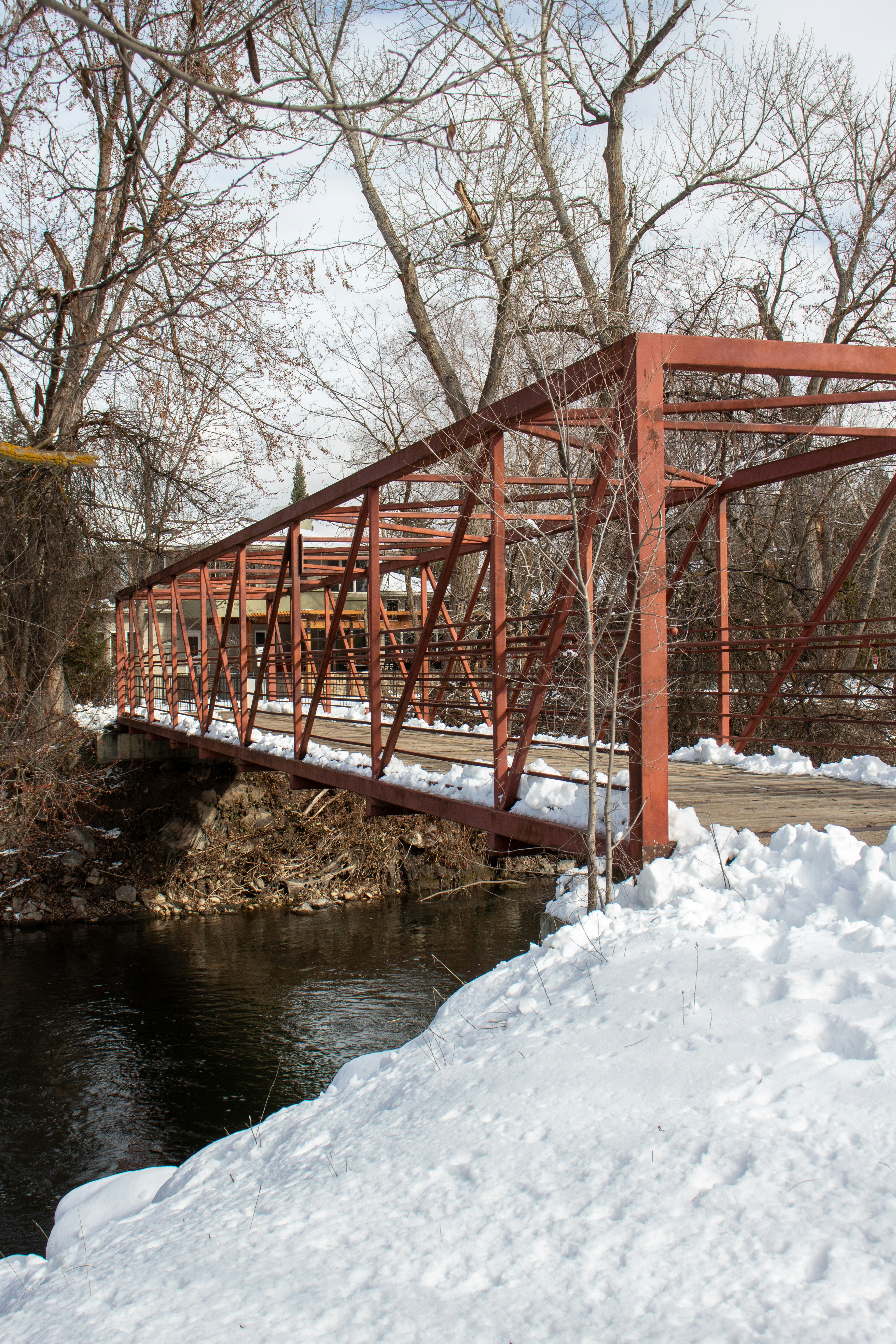 Red Iron Bridge Crossing a Snow-Covered River in Winter Light