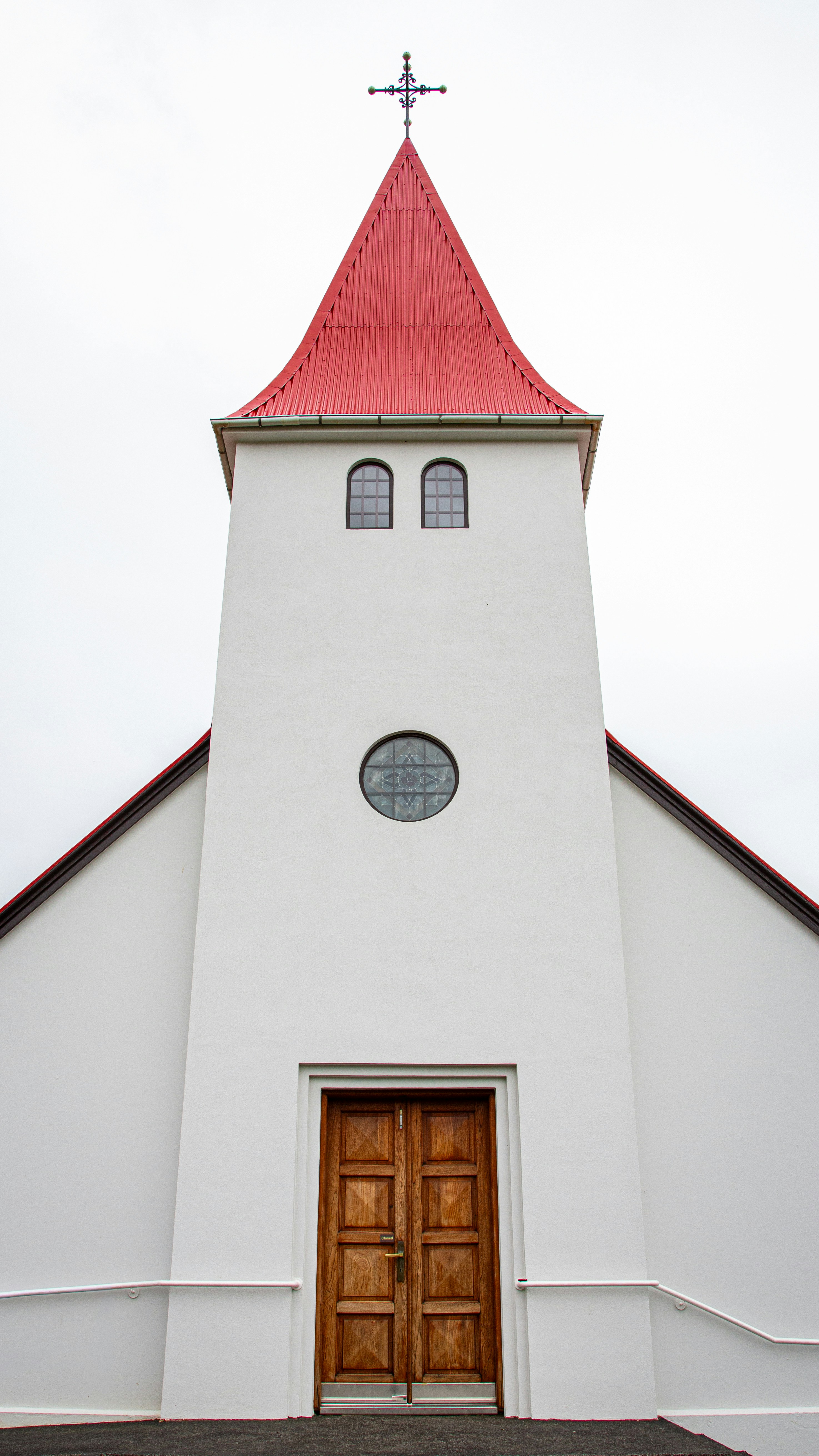 White church with a bold red steeple and wooden door
