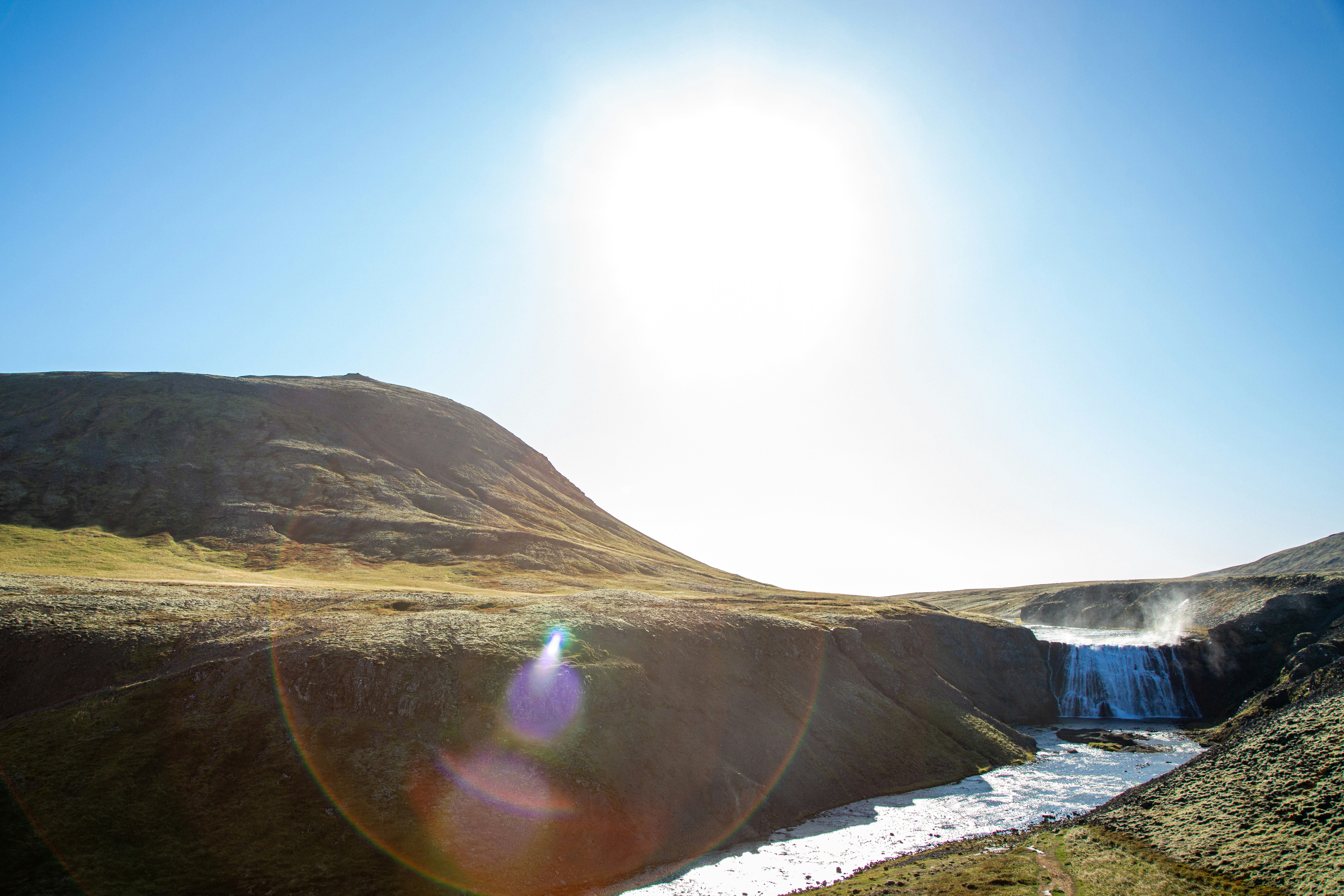 Sunlit Basin and Waterfall Under a Bleak Plateau