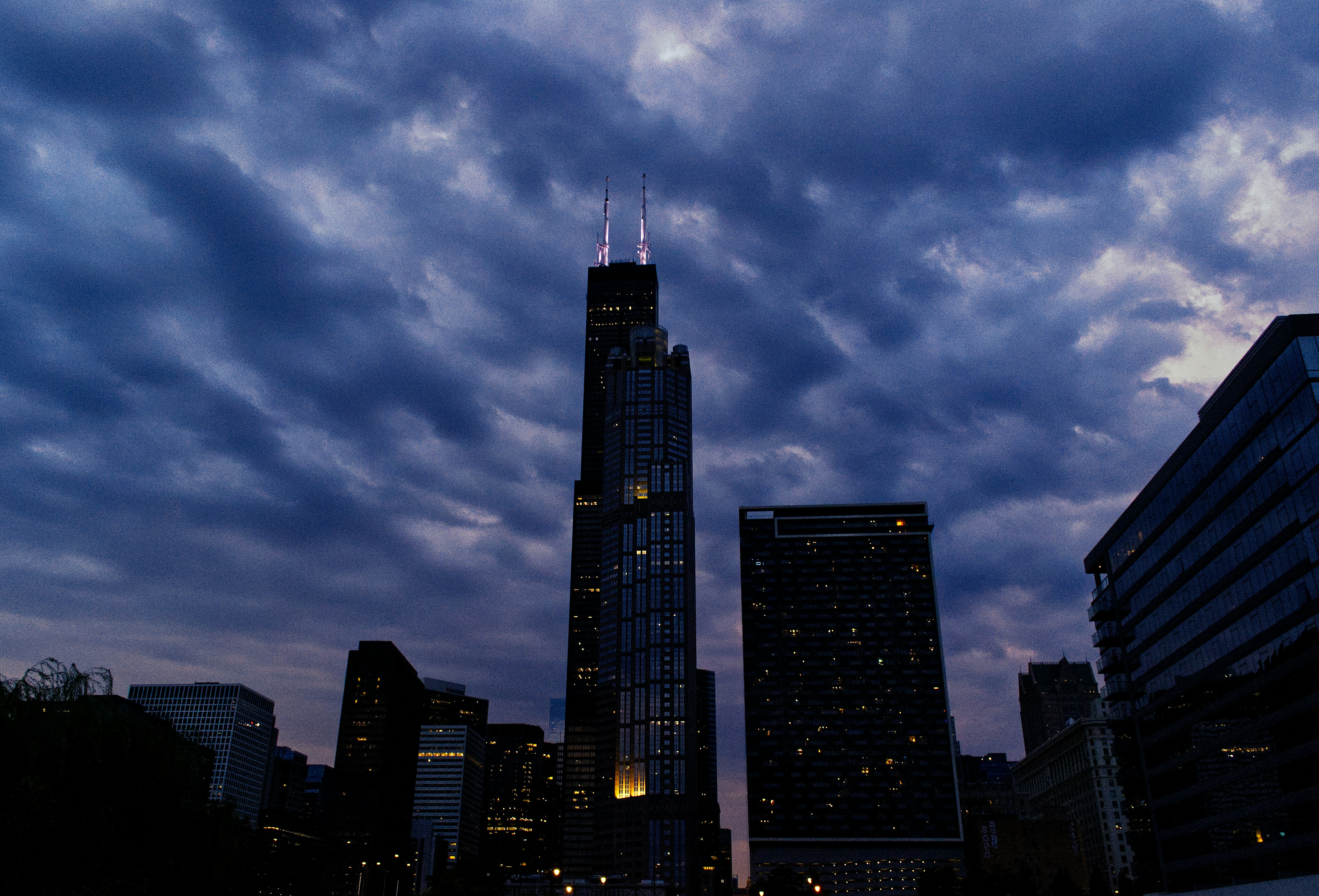 Midnight Sentinel: Downtown Skyscraper Silhouette Under Clouded Indigo Sky
