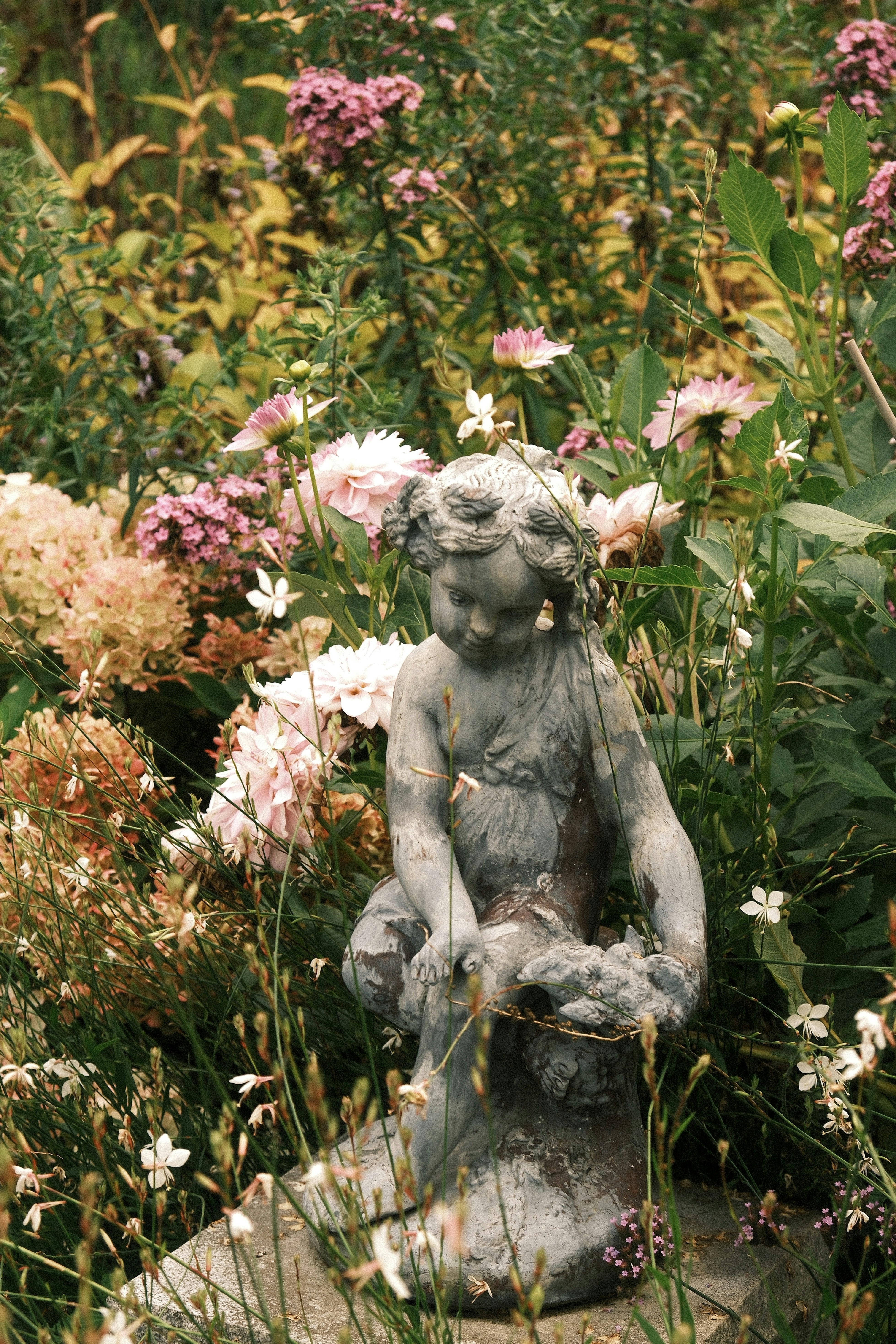 Whispering Garden Guardian: A Weathered Angel Among Blossoms