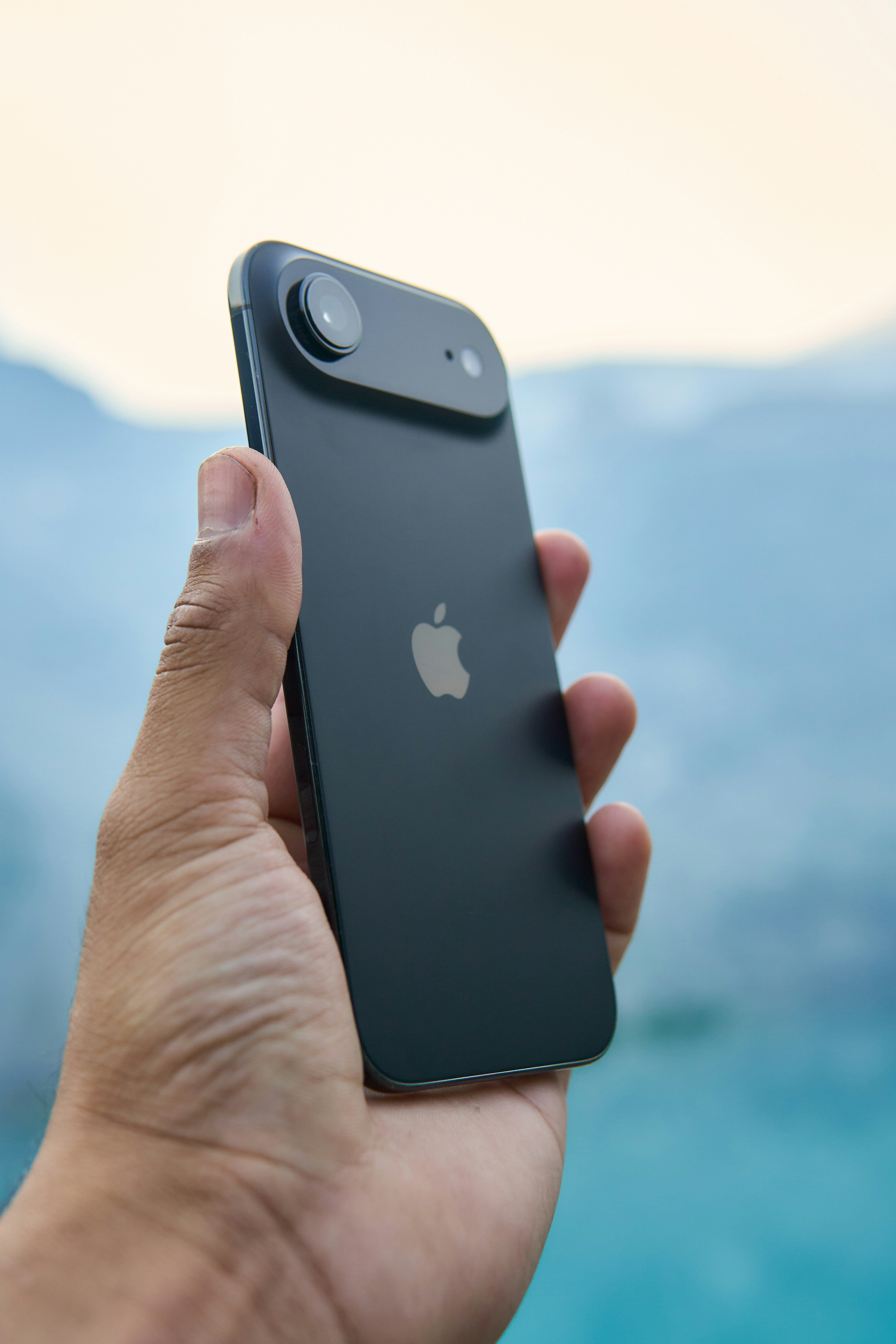 Holding Tech in Focus: A Close-Up of a Hand Gripping an Apple iPhone