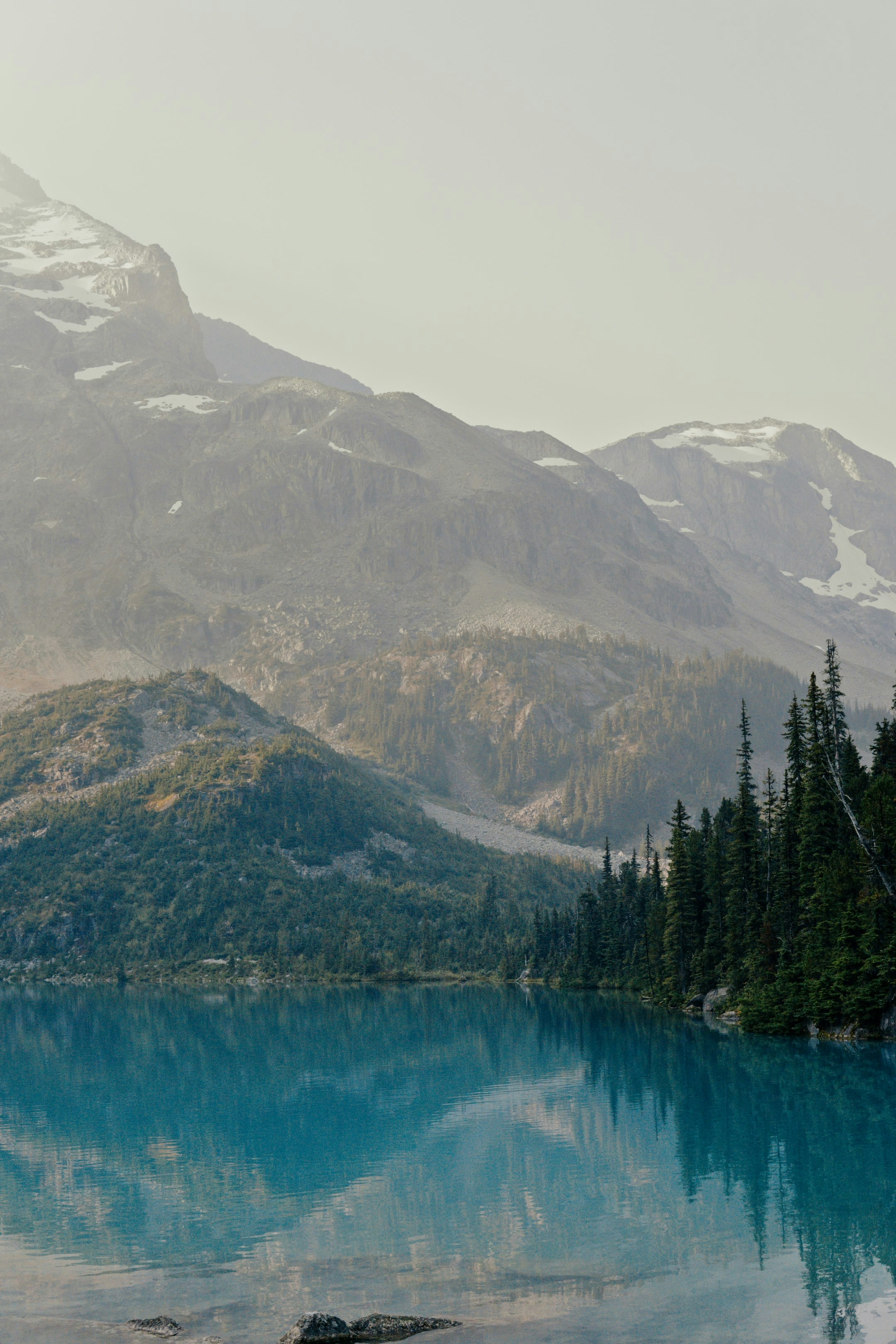 Glacial Mirror: turquoise lake at the edge of pine forests and towering snow-capped peaks