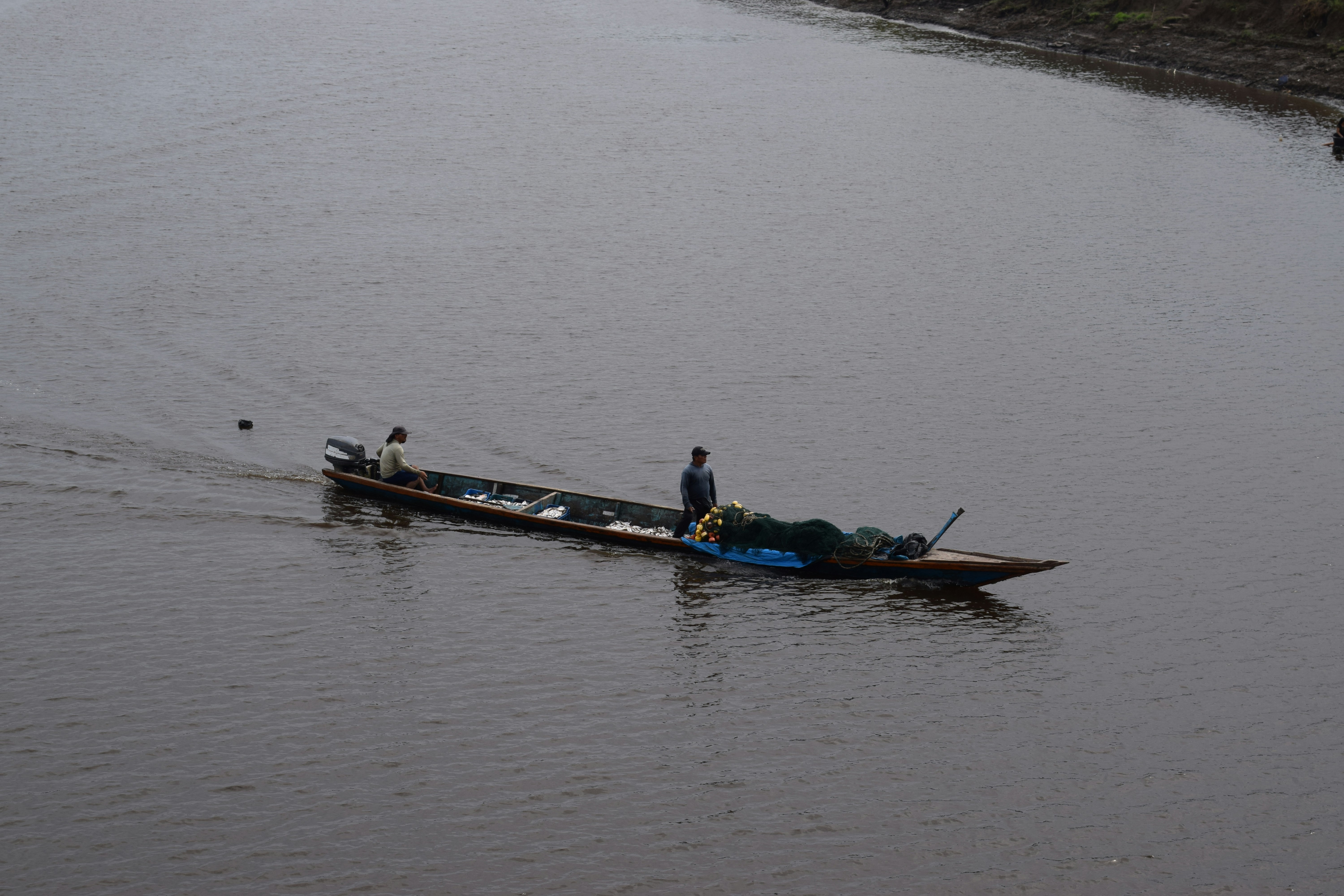 Long-tail Boat Patrolling a Misty Riverside