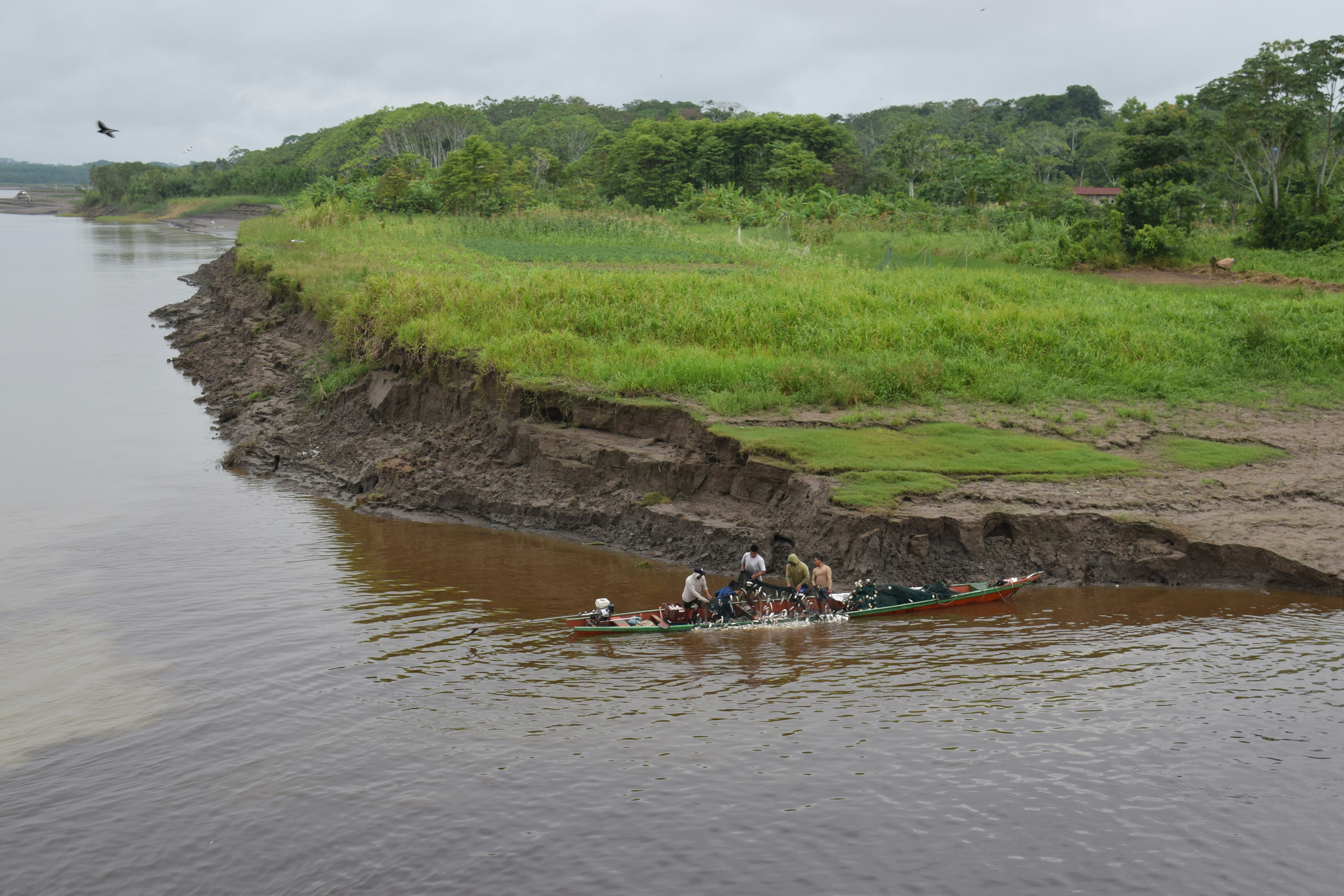 A group of people in a small boat fishing on a muddy river