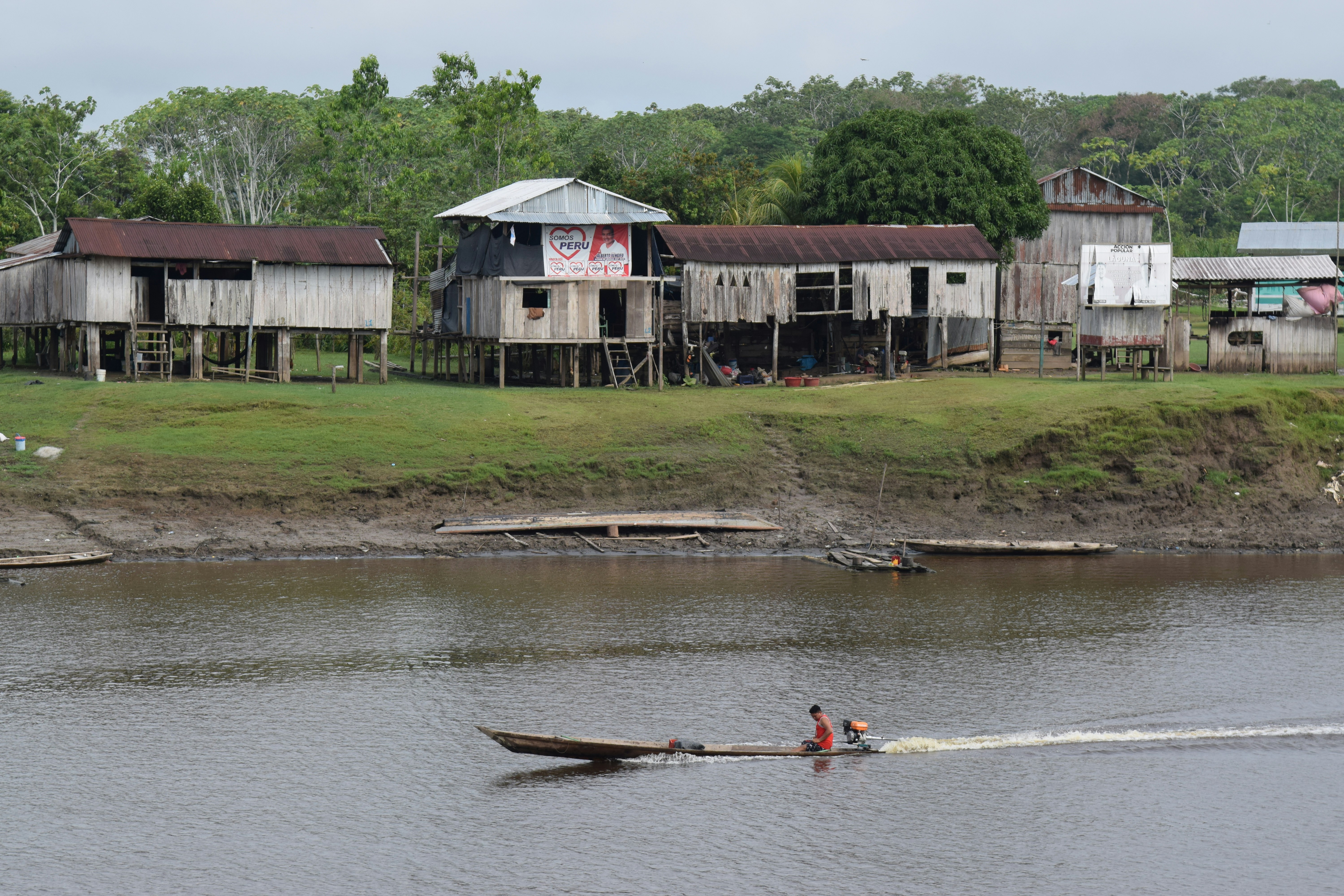 Riverside Village at Dusk: Stilt Homes Overlooking a Boat on the River