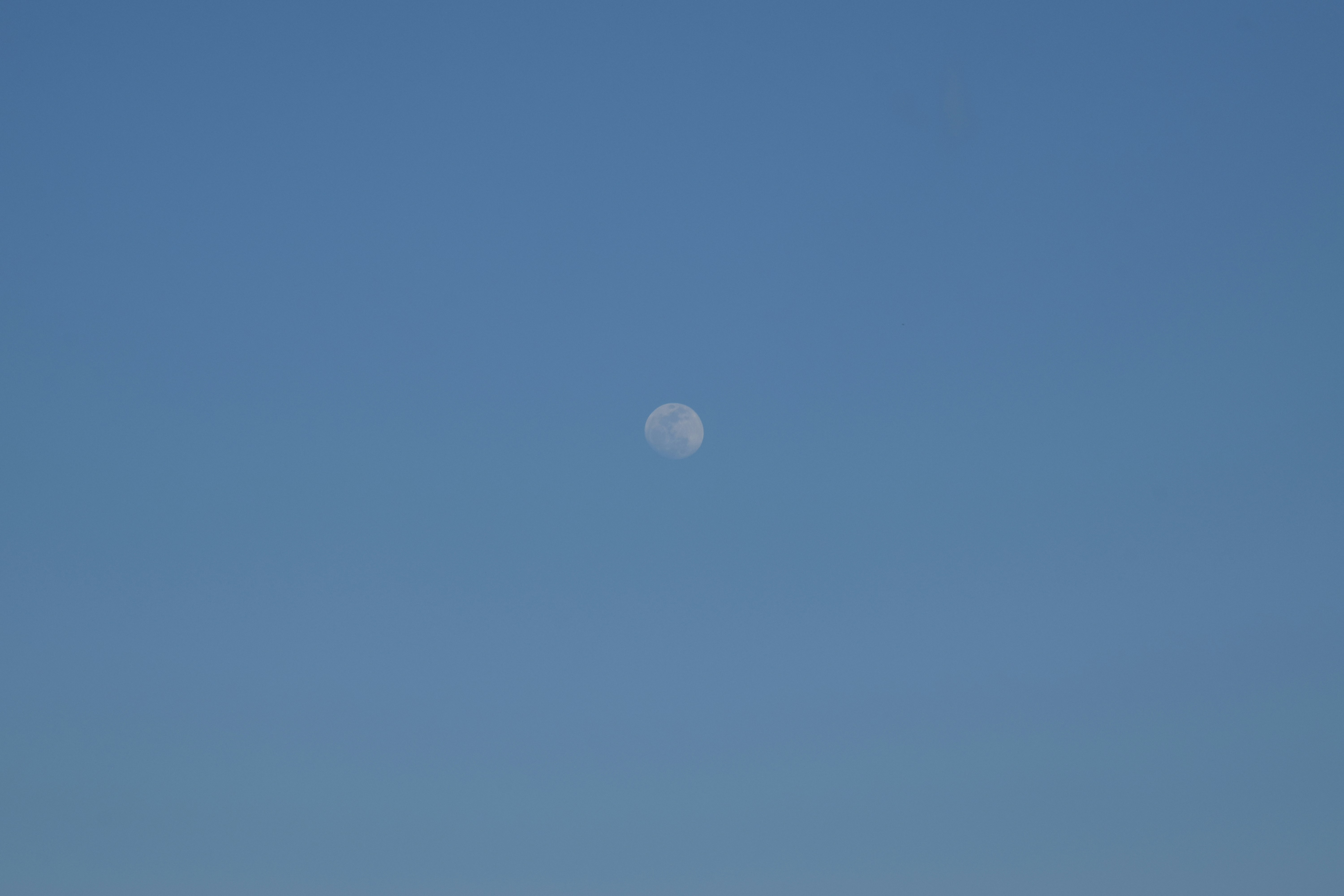 Moonlight in a Clear Noon: A lone Moon in a Calm Sky