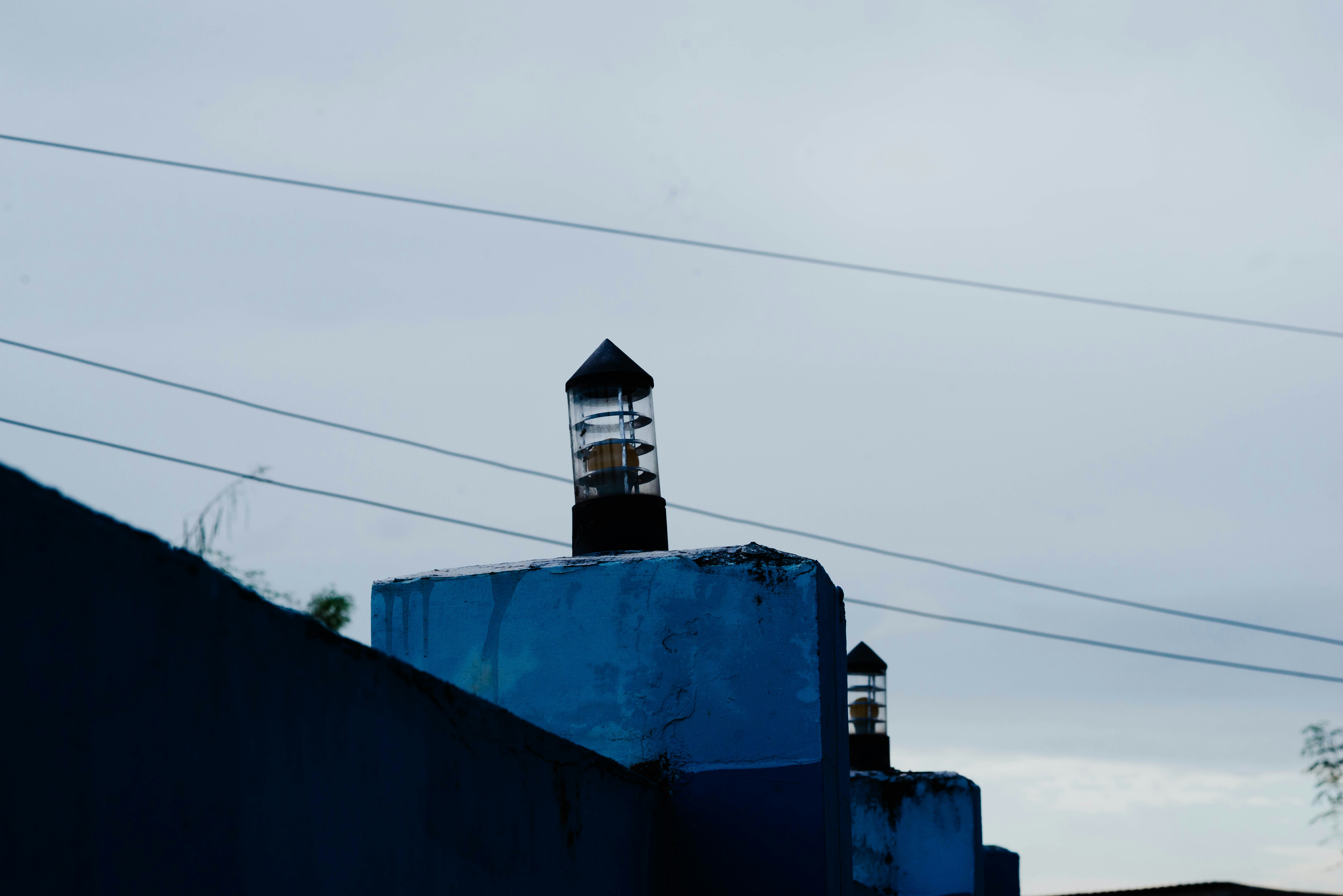 Blue concrete wall with perch of chimneys under pale sky