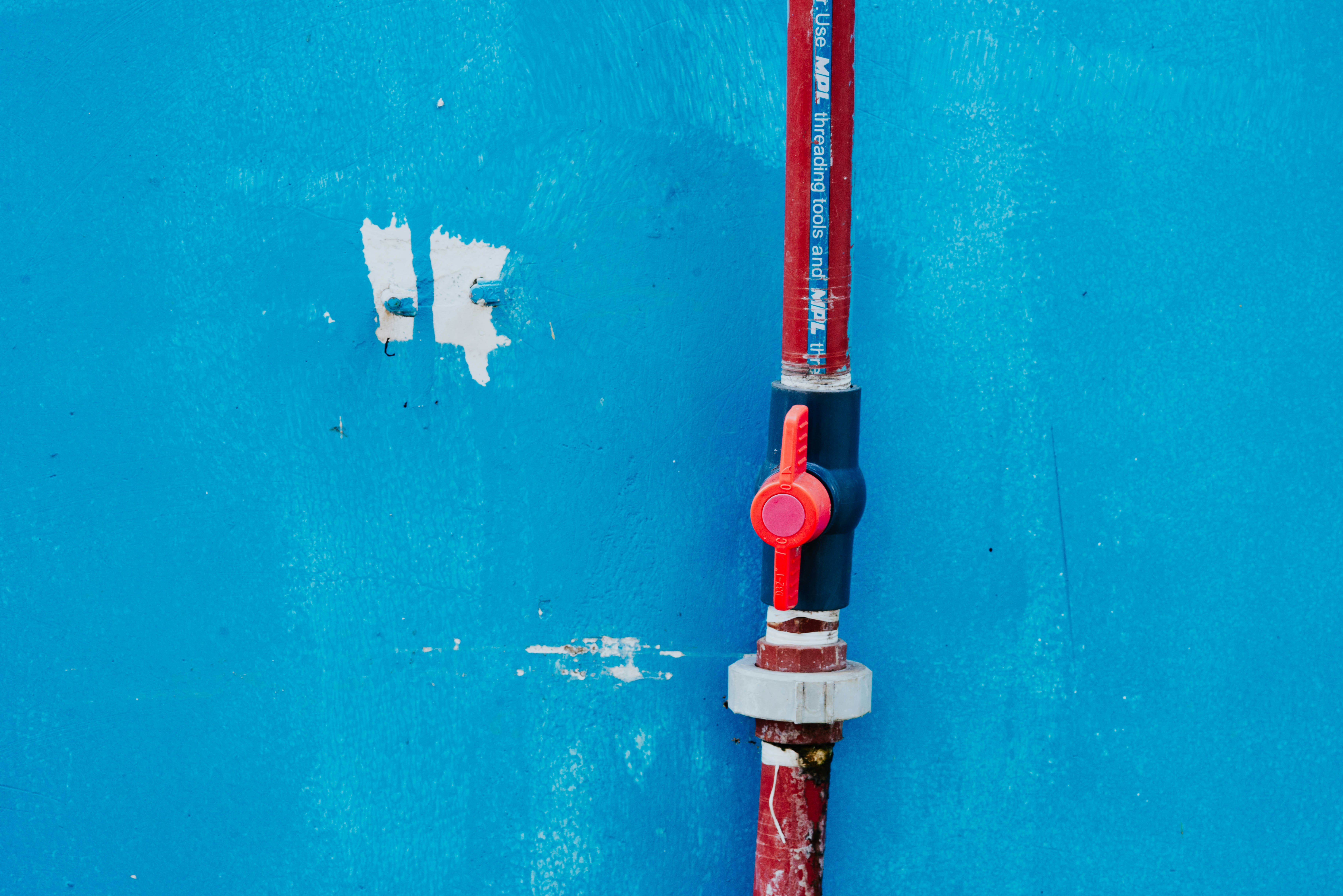 Red Valve on a Worn Blue Wall