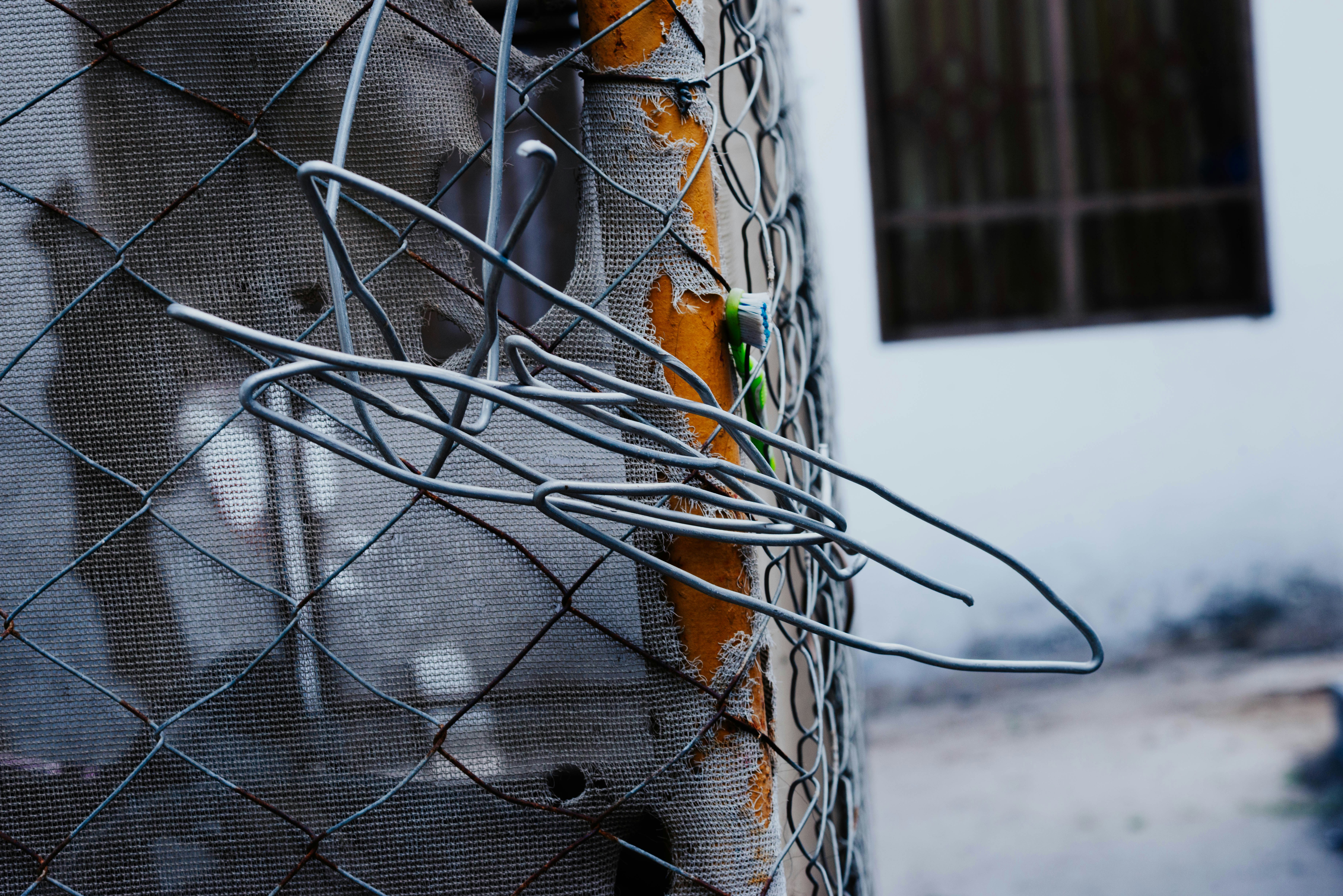 Barbed Veins: Threaded Fence Encasing a Worn Wall