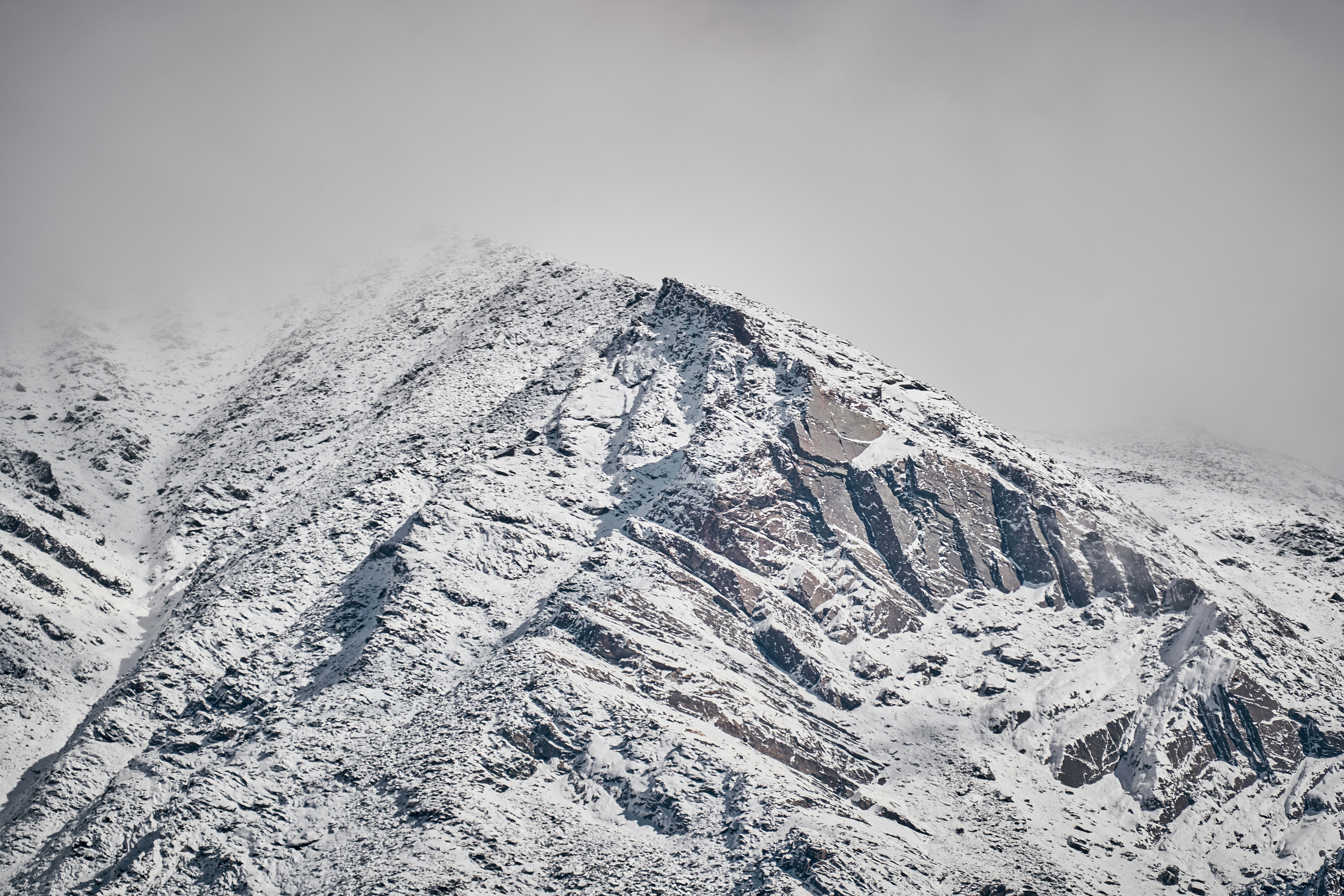 Snow-clad ridge carved by wind under a drifting veil
