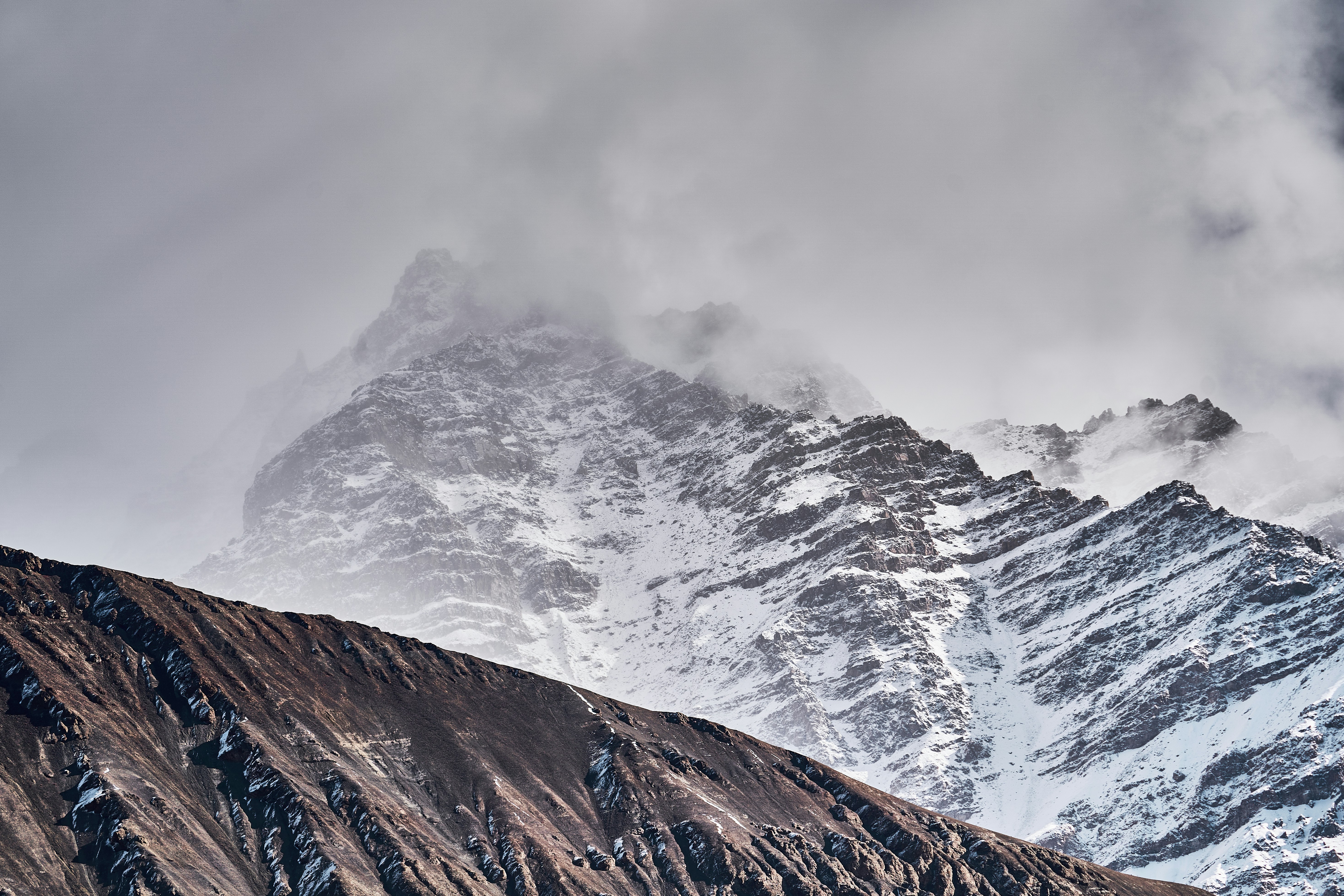 Snow-clad Ridge Emerging from Mist Over Rugged Slopes