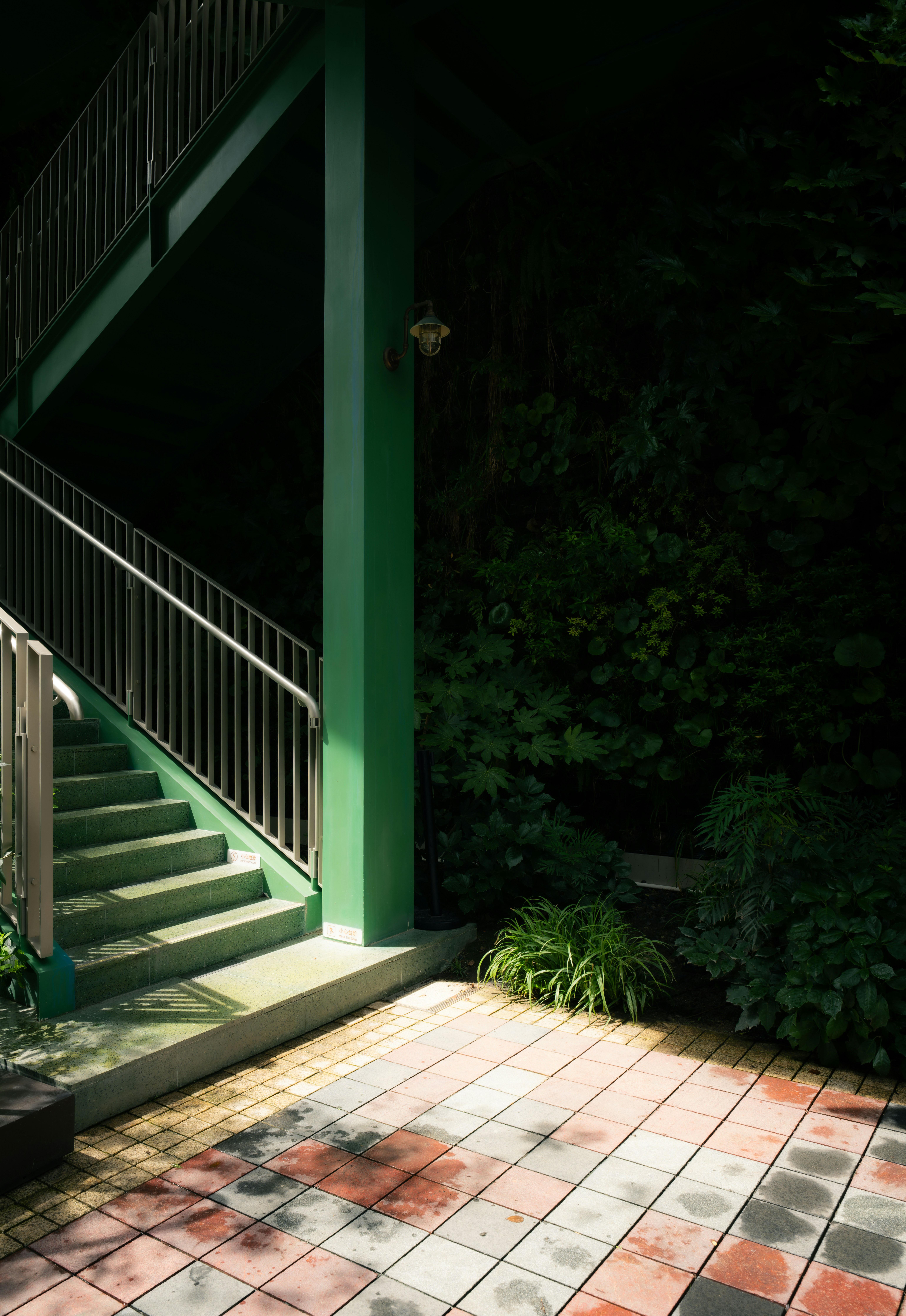 Green Staircase Under a Shaded Balcony