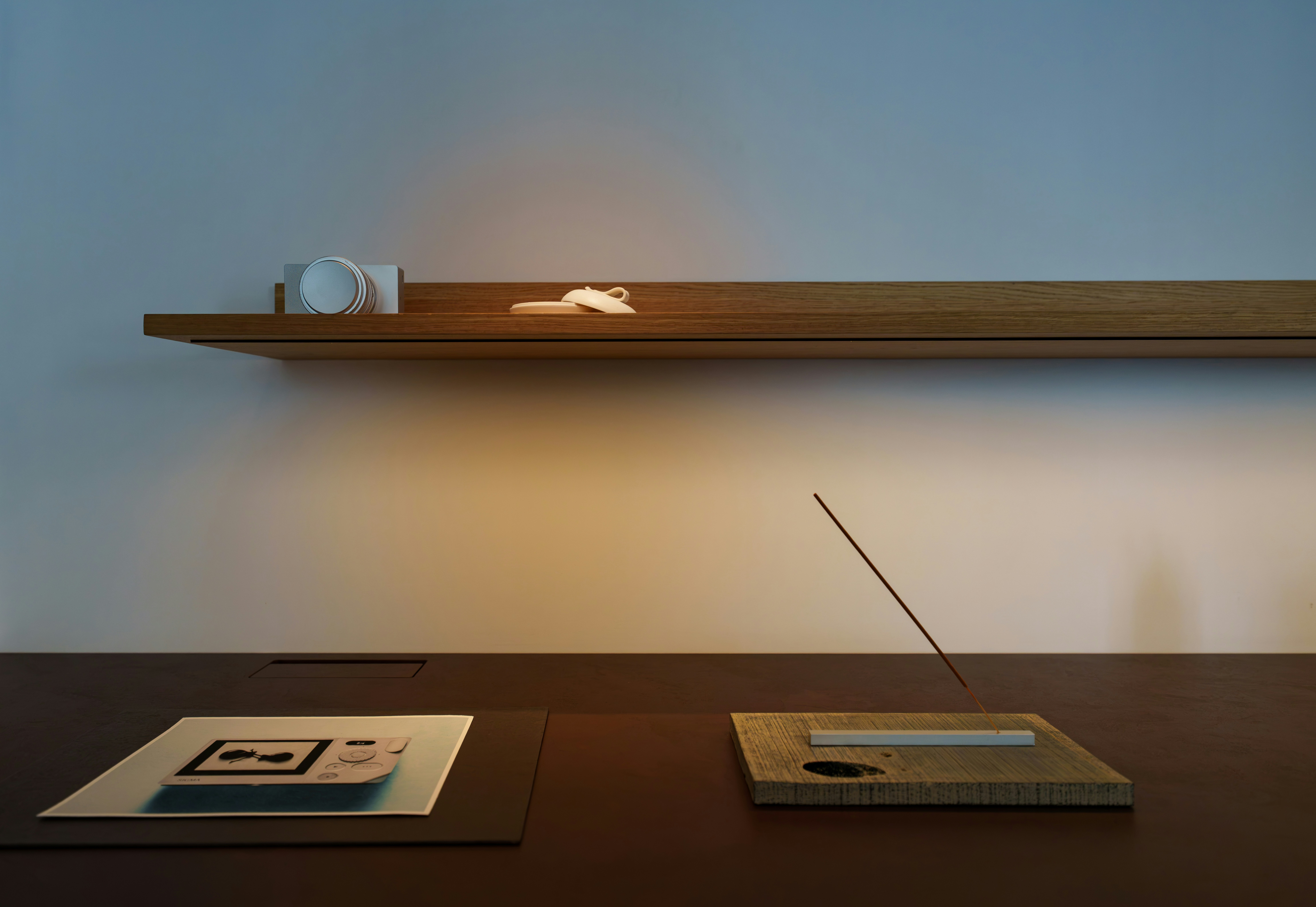 Minimalist desk with a slim shelf and objects bathed in warm light