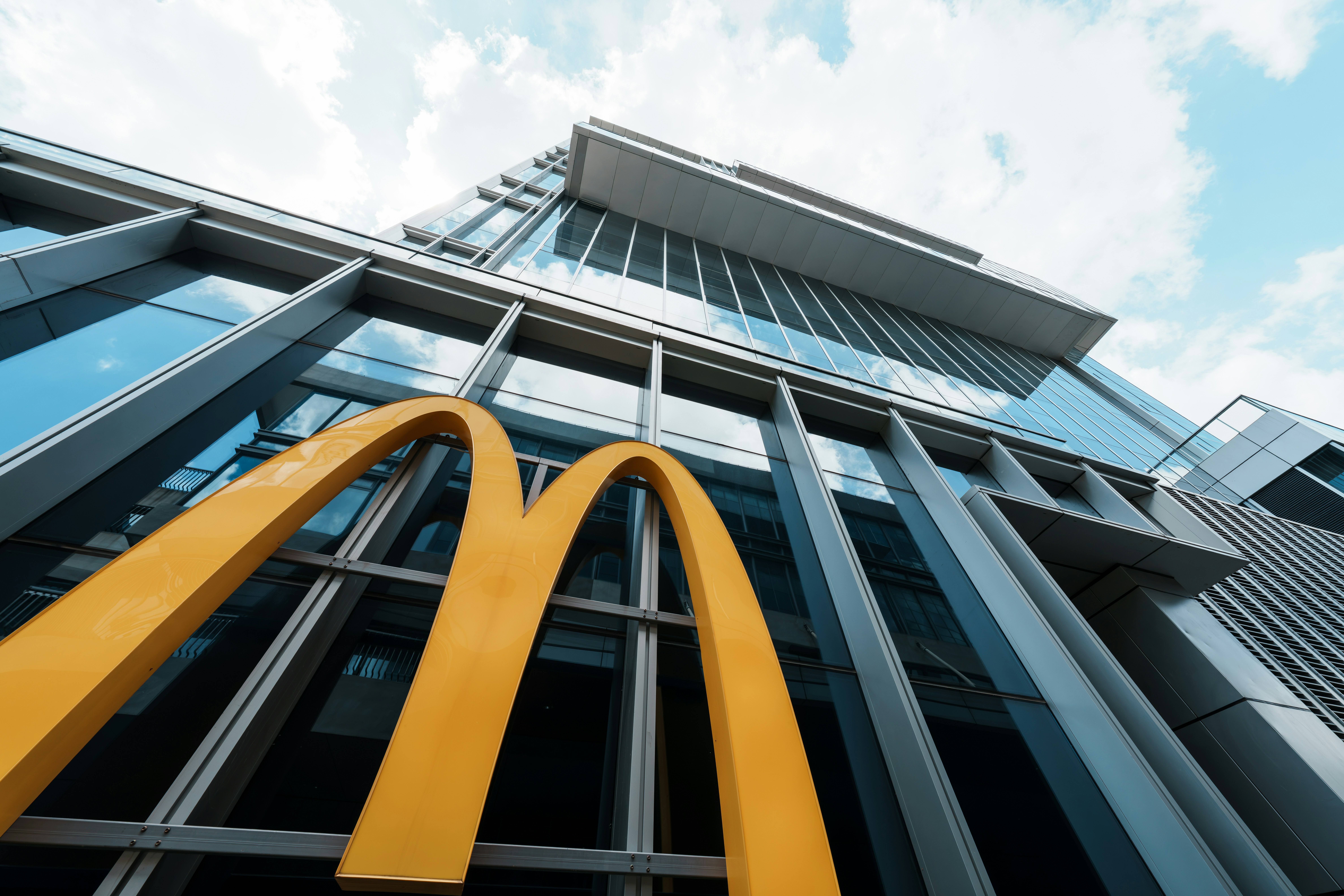 Golden Arches Against Glass Sky: A McDonald's Sign Framed by Modern Architecture