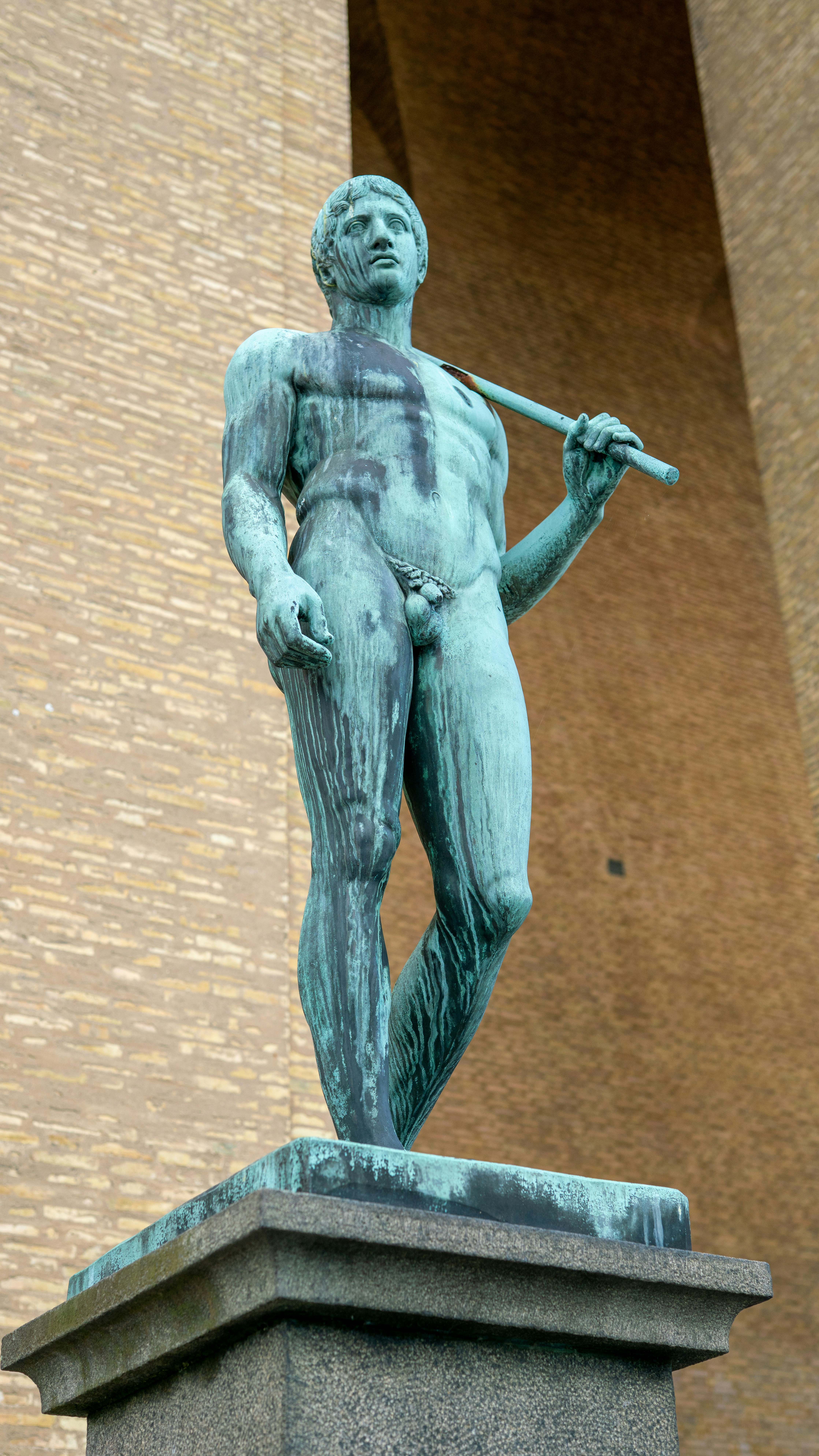 Bronze-Green Static: A Roman Figure with a Cane in Front of Brick Walls