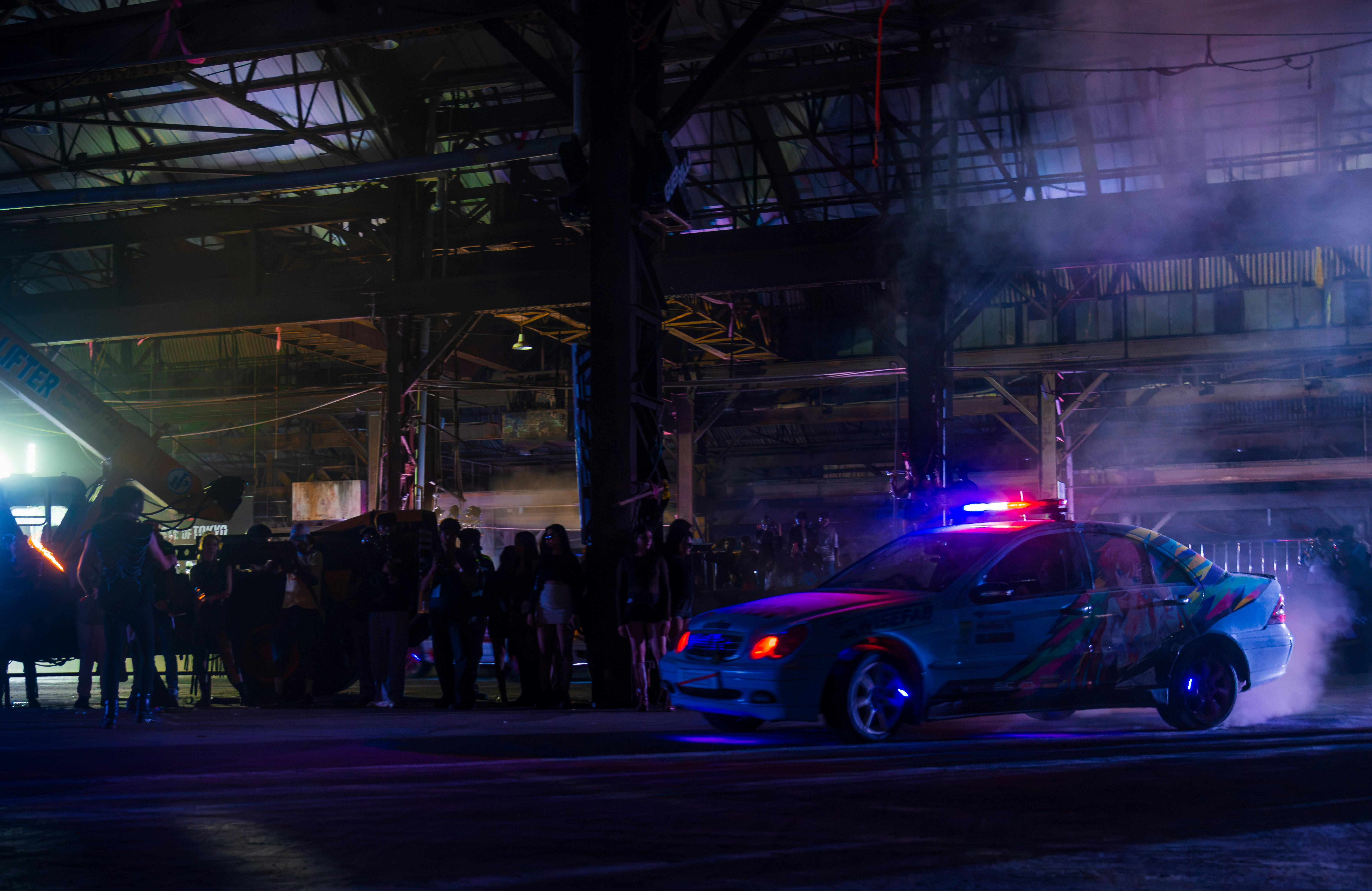 Blue Police Car in Motion: Night Show Under Industrial Beams