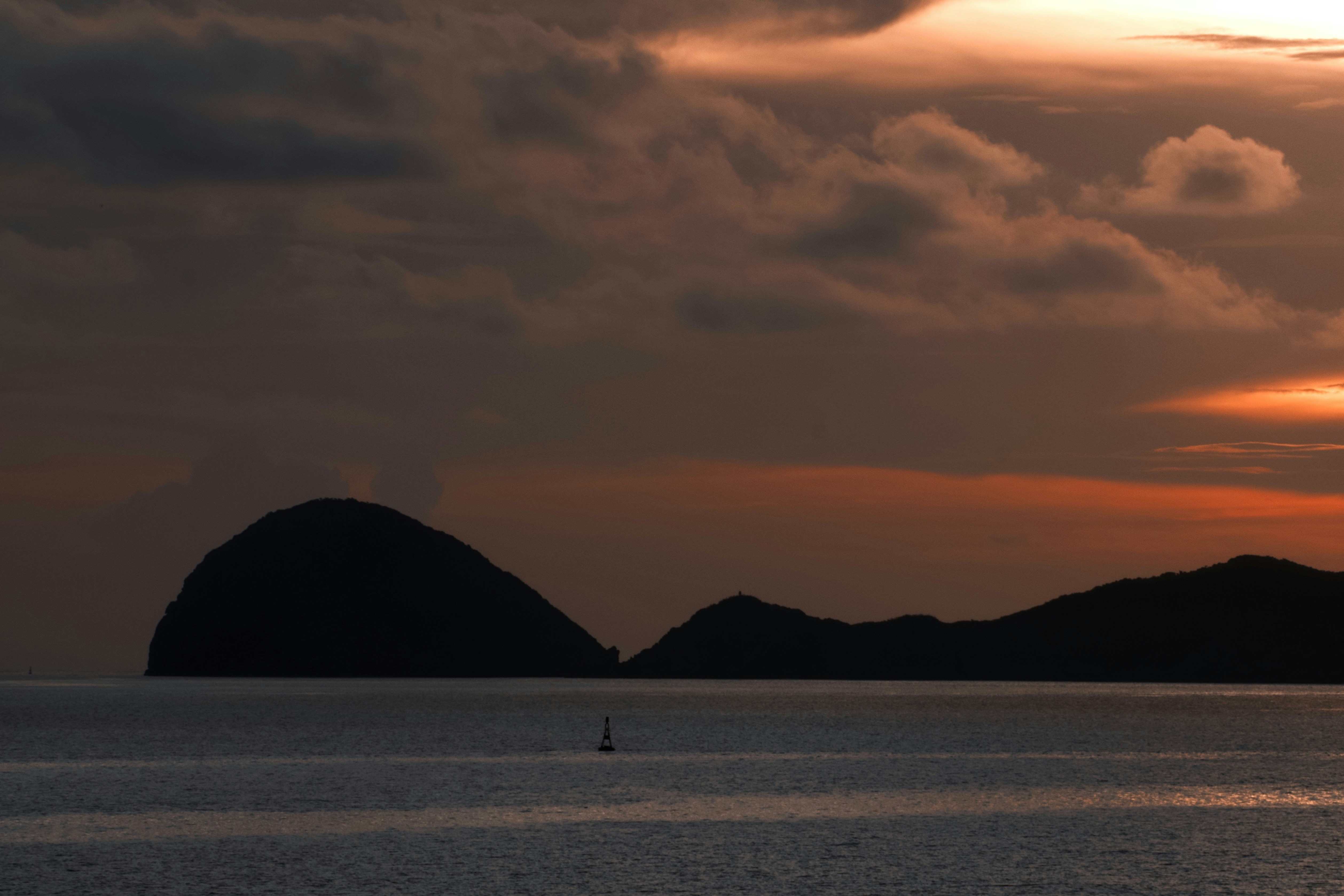 Dusk over the Quiet Horizon: Island Silhouette at Sea