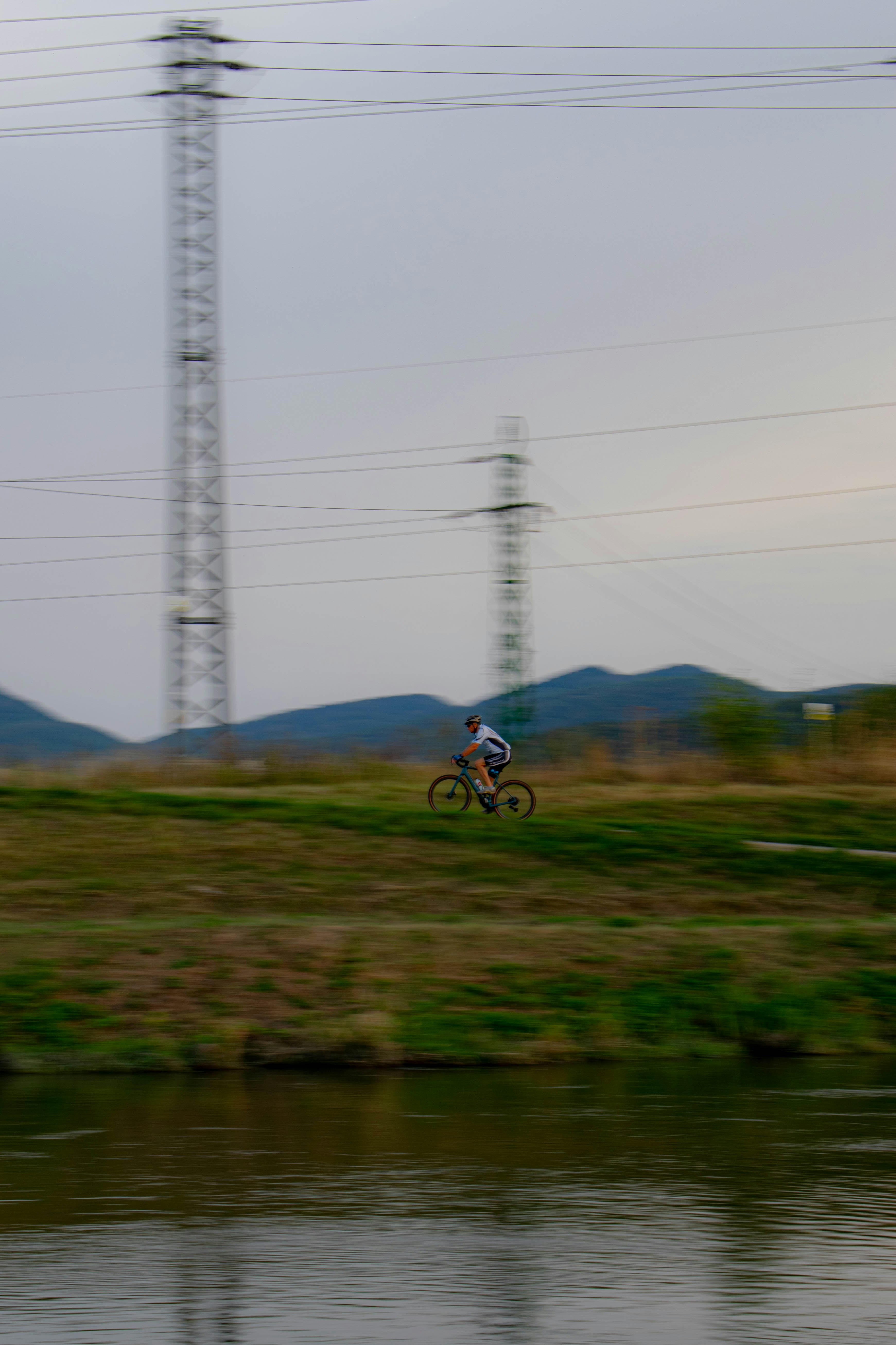 Ridge Run: Cyclist Streaking Across a Quiet River Plain