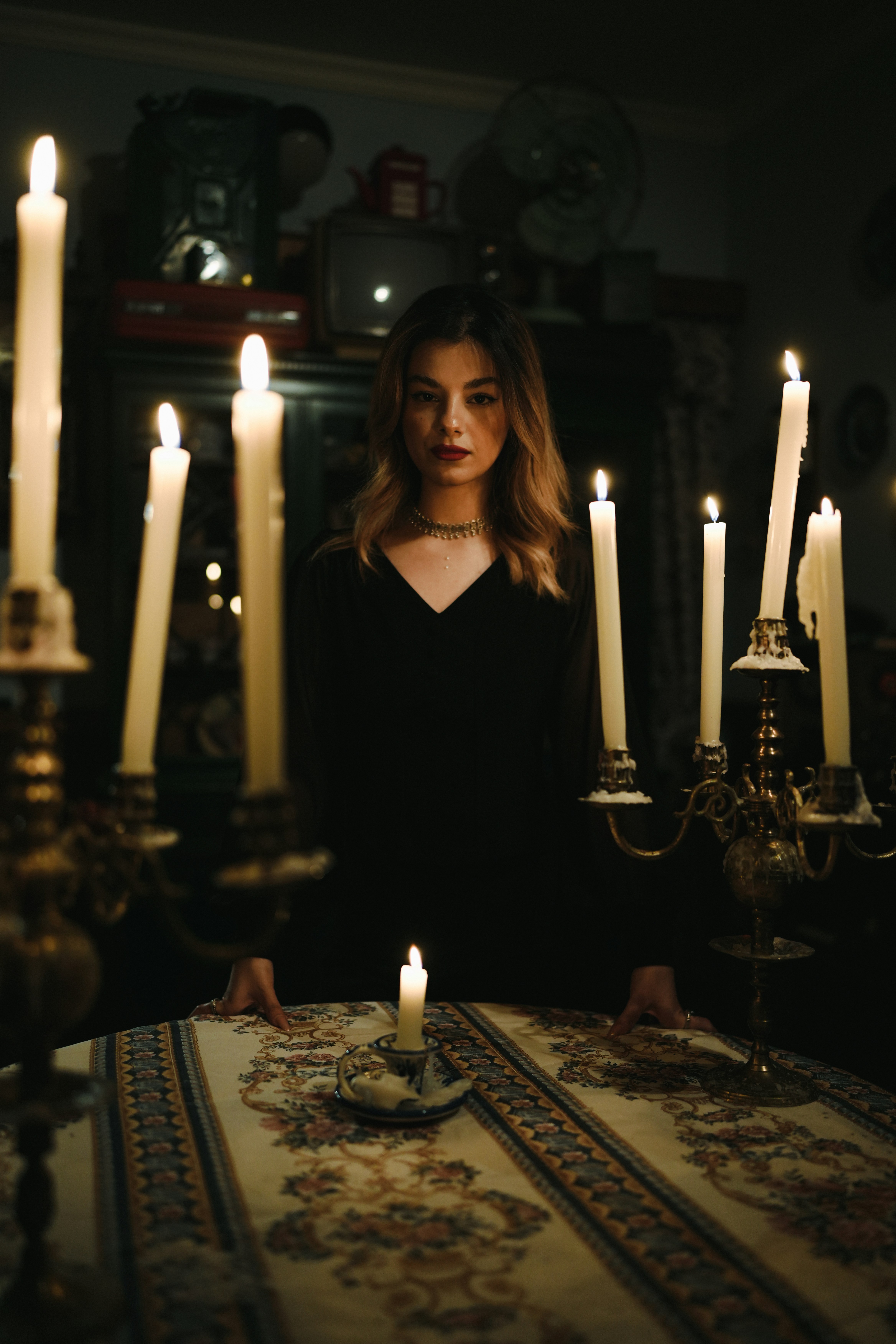A woman in a black dress behind a table with lit candles