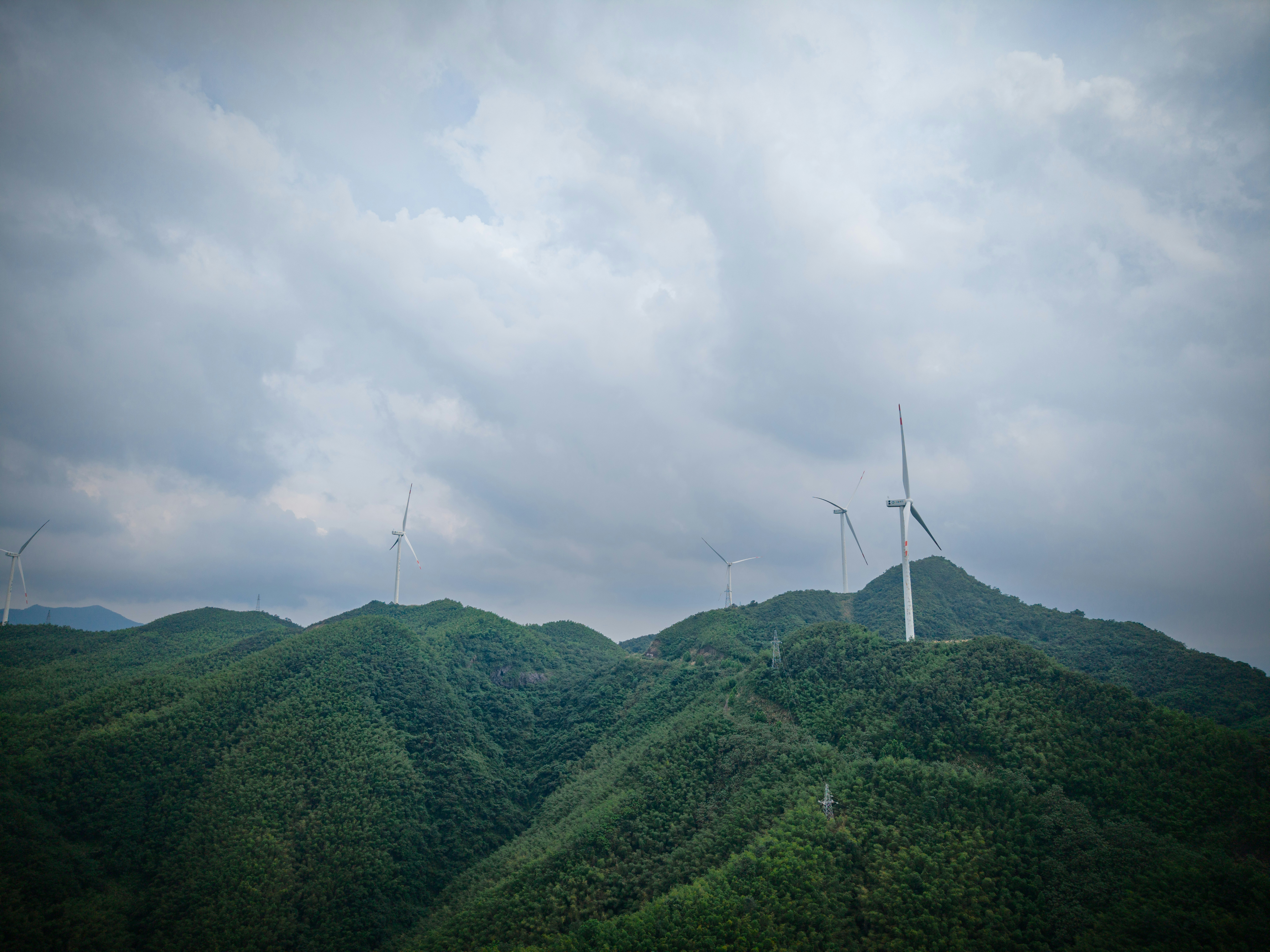 Verdant Ridges with Tall Wind Turbines under a Cloudy Sky
