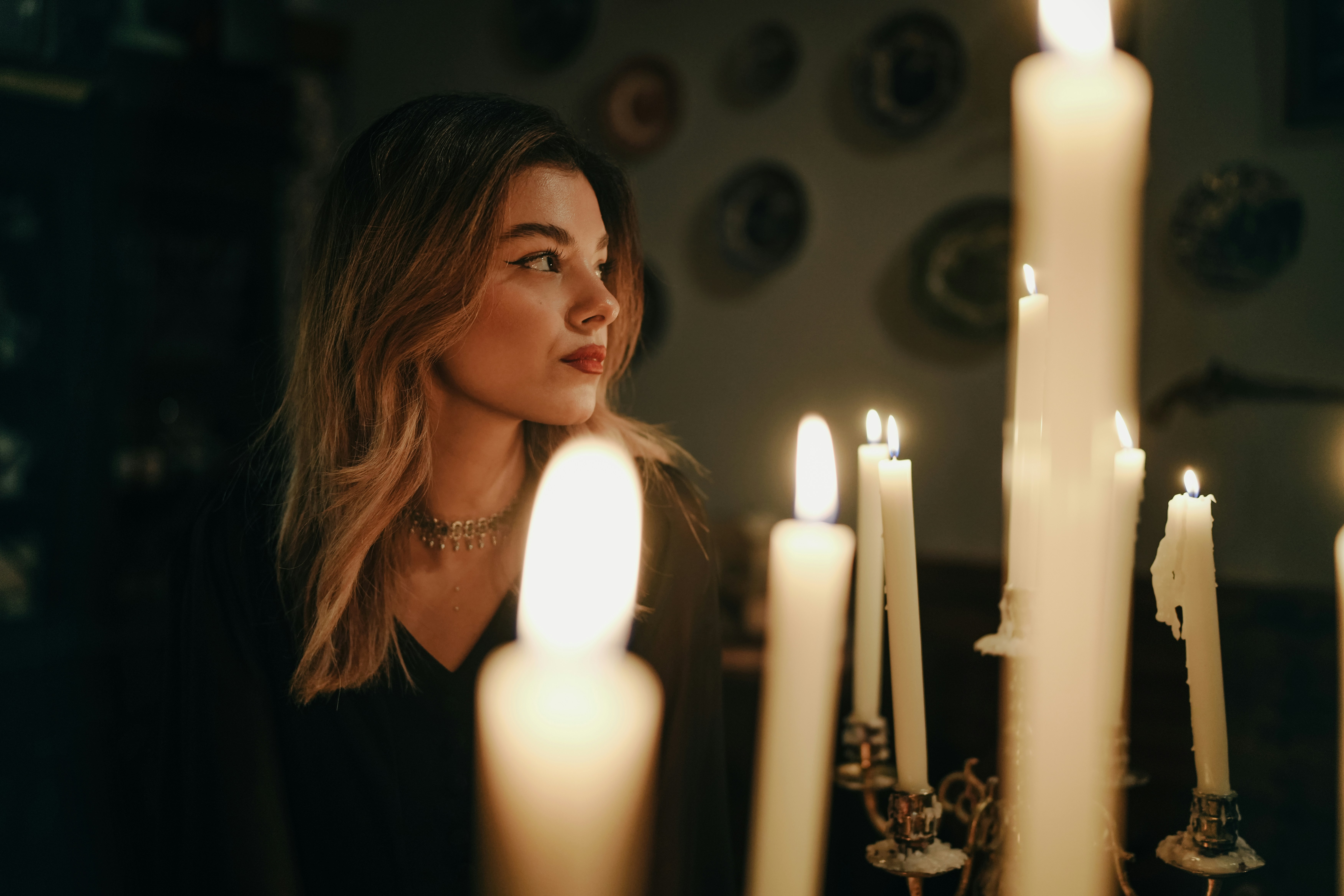 A woman in a dark top beside a candelabra with glowing white candles