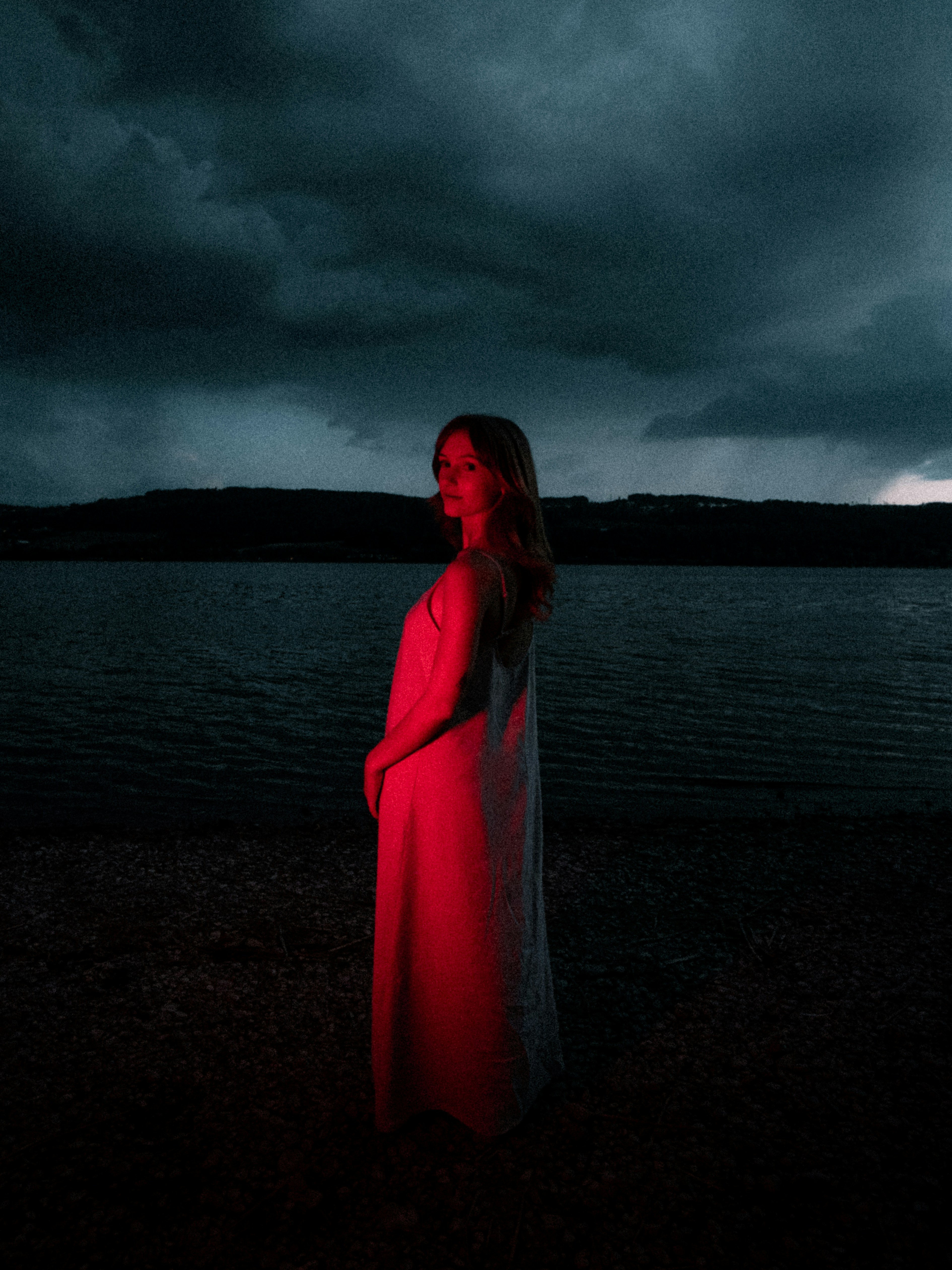 Red-lit silhouette by the darkened lake