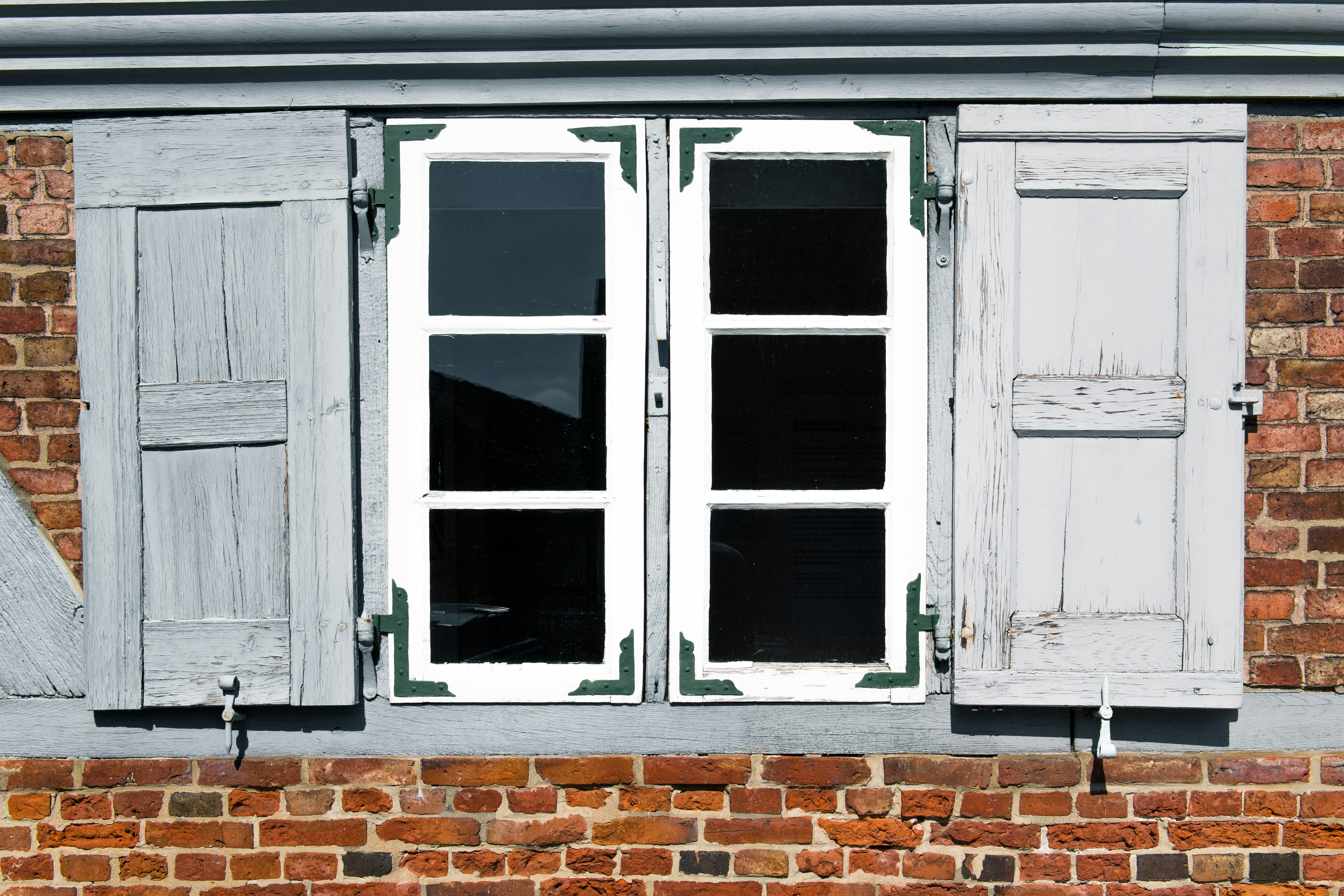 Weathered Window Duo: A Brickwork Frame of Shuttered Charm