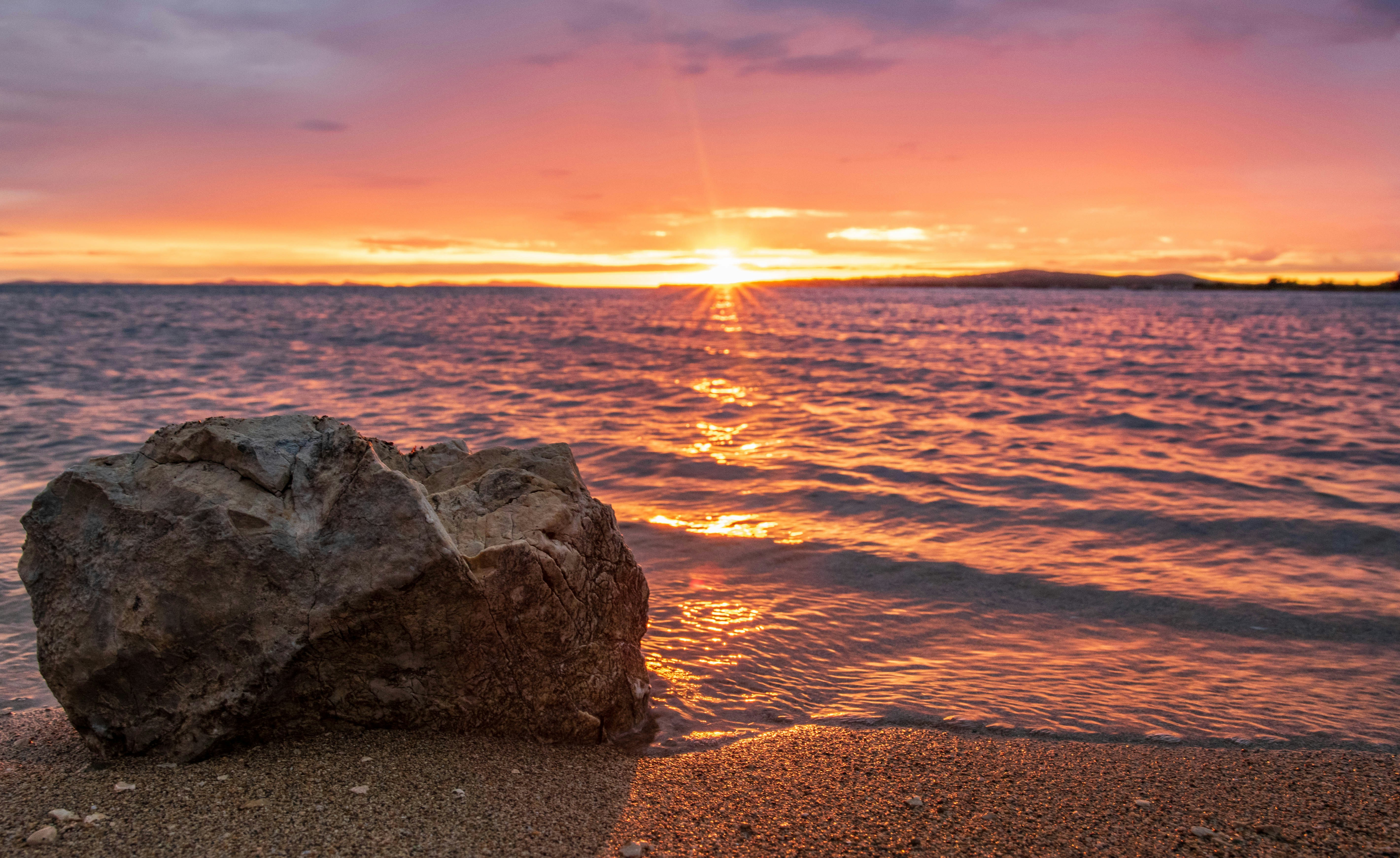 Sunlit Shoreline: A Quiet Rock, A Distant Horizon