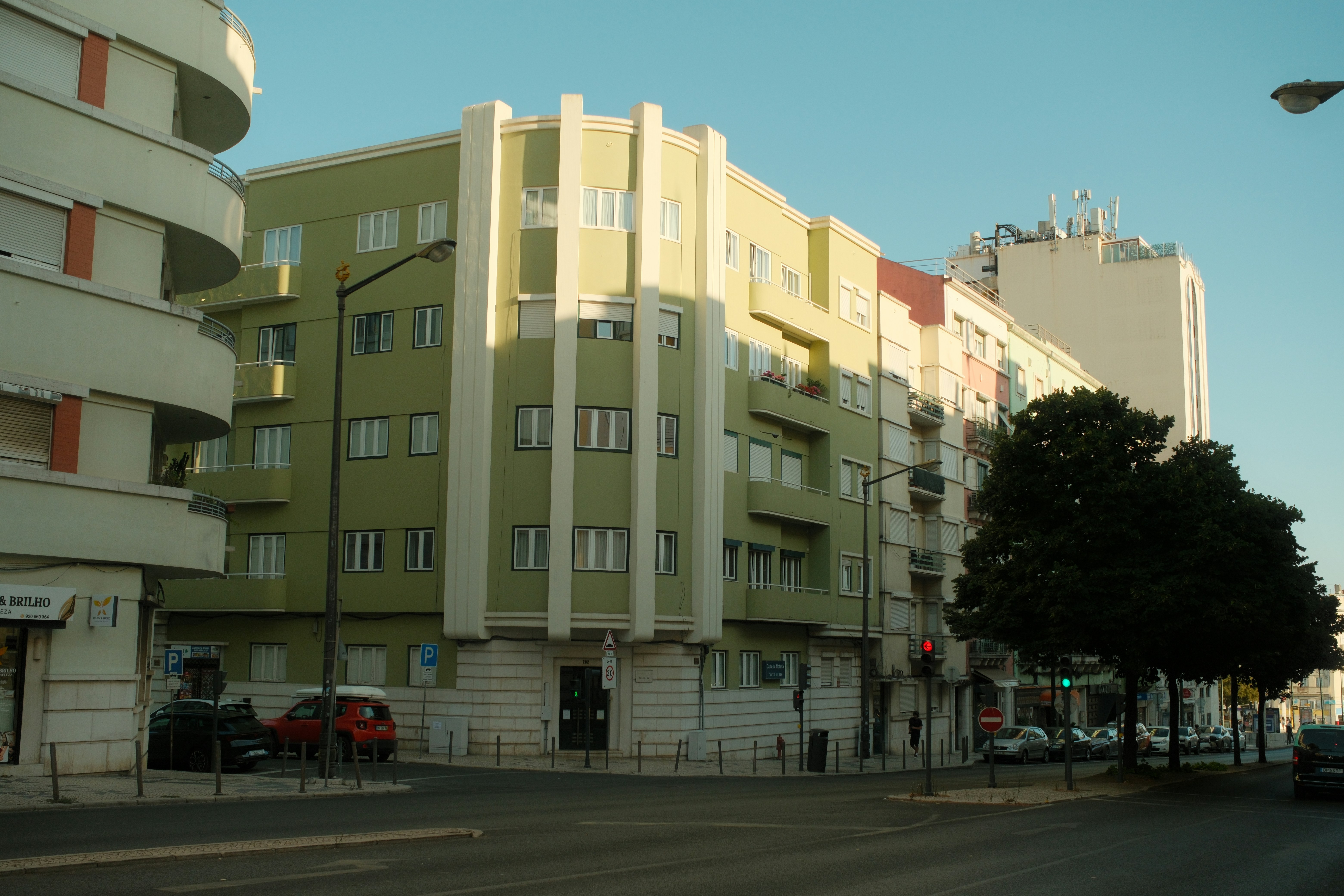 Sunlit Green Facade: A Quiet Street Corner Under Clear Sky