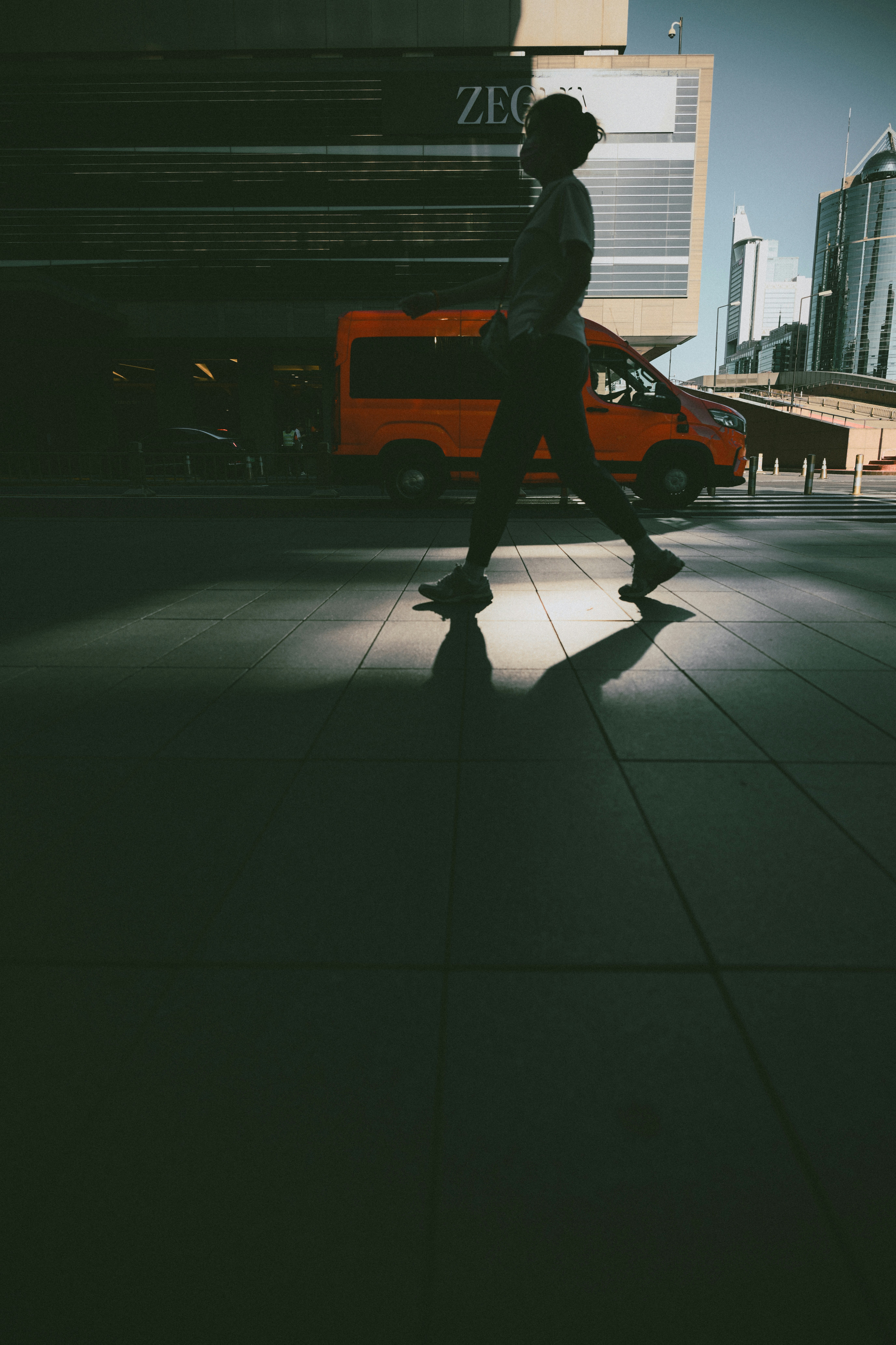 Shadowed Stride: City Pedestrian Crossing a Dappled Fade