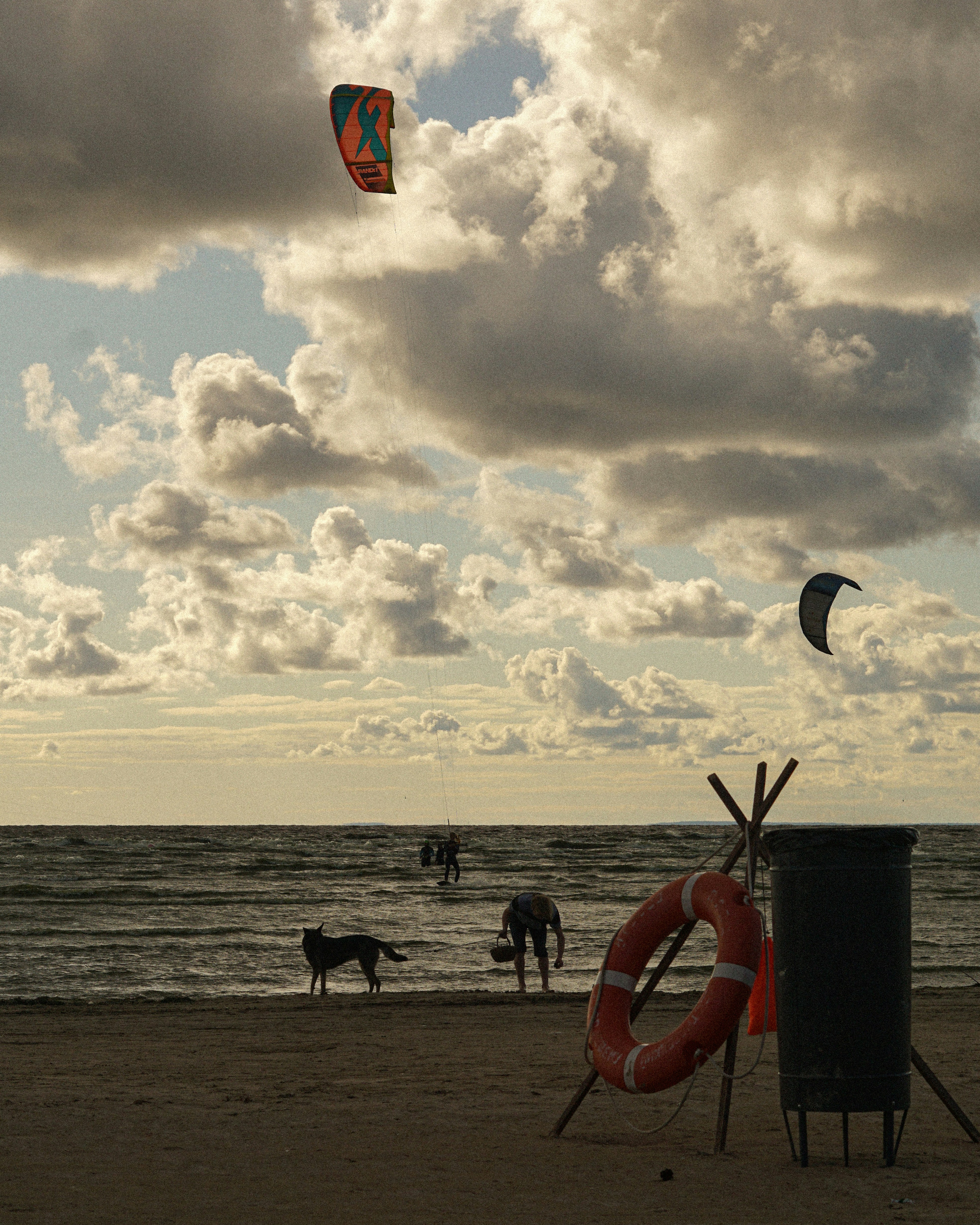 Kite Surfers at Dusk: Lifebuoy and Sail Against a Cloudy Horizon