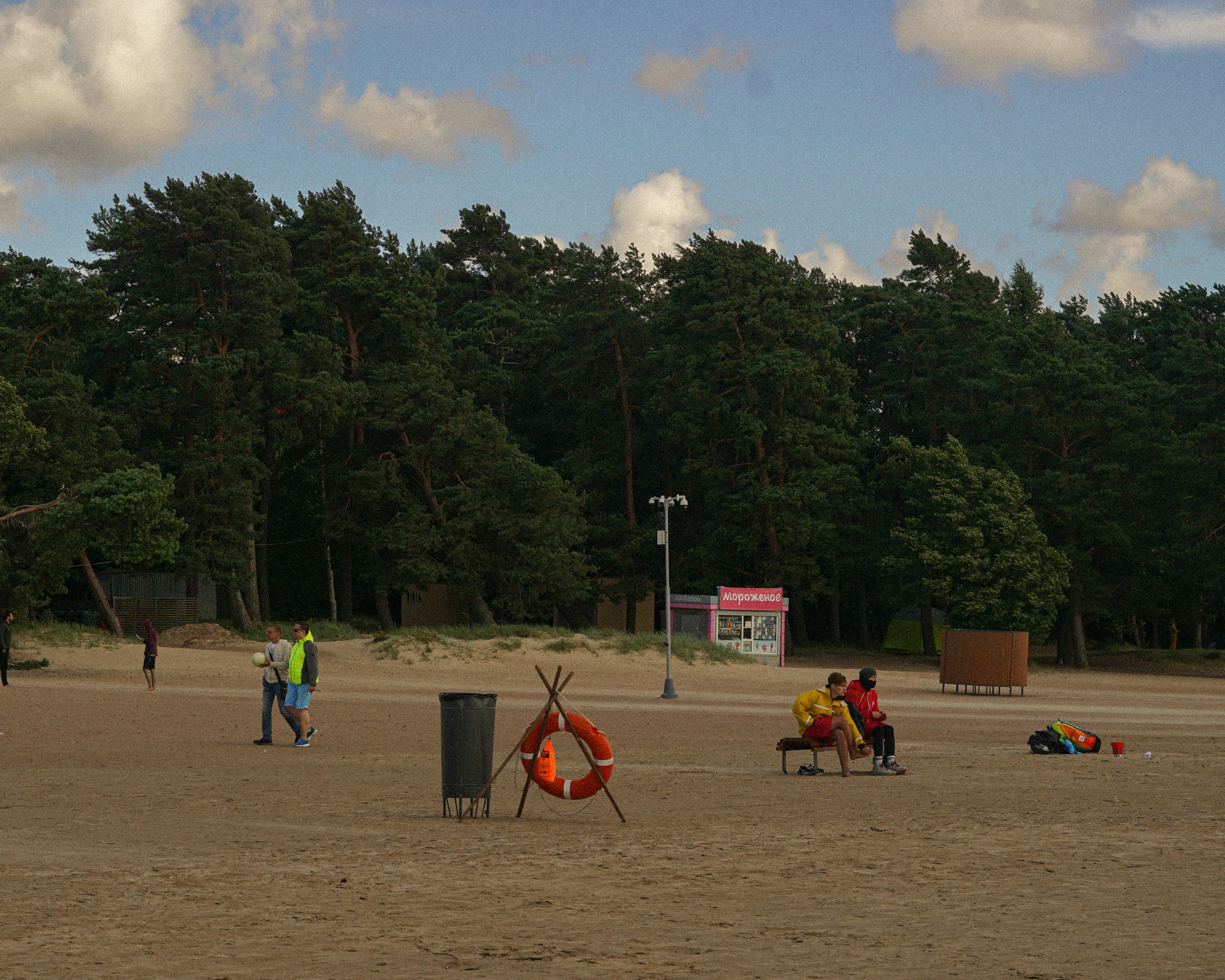Lifebuoy Guard and Seated Visitors on a Sandy Park Beach