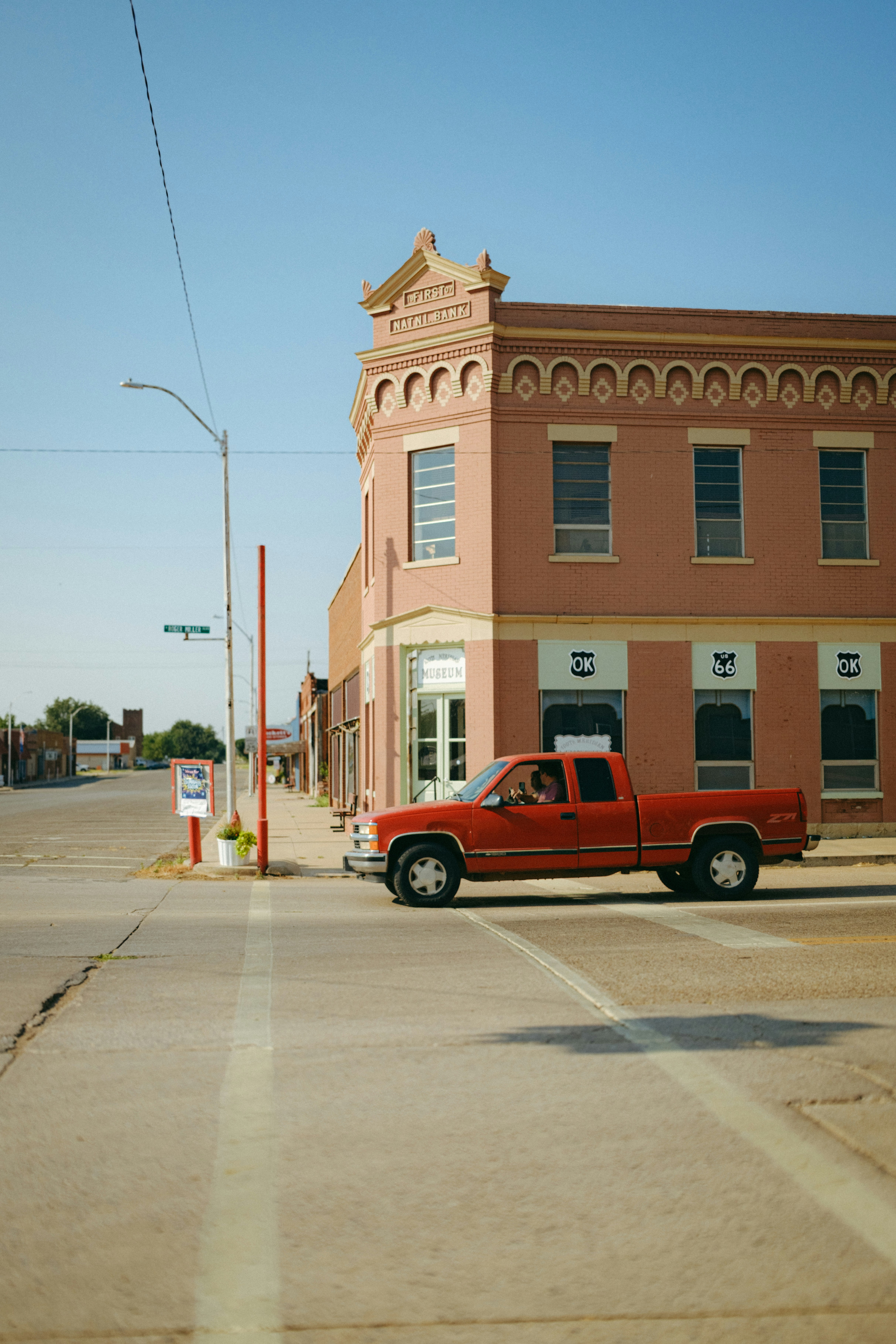 Sunlit Corner: A Brick Town Brewery and Red Pickup Under a Clear Sky