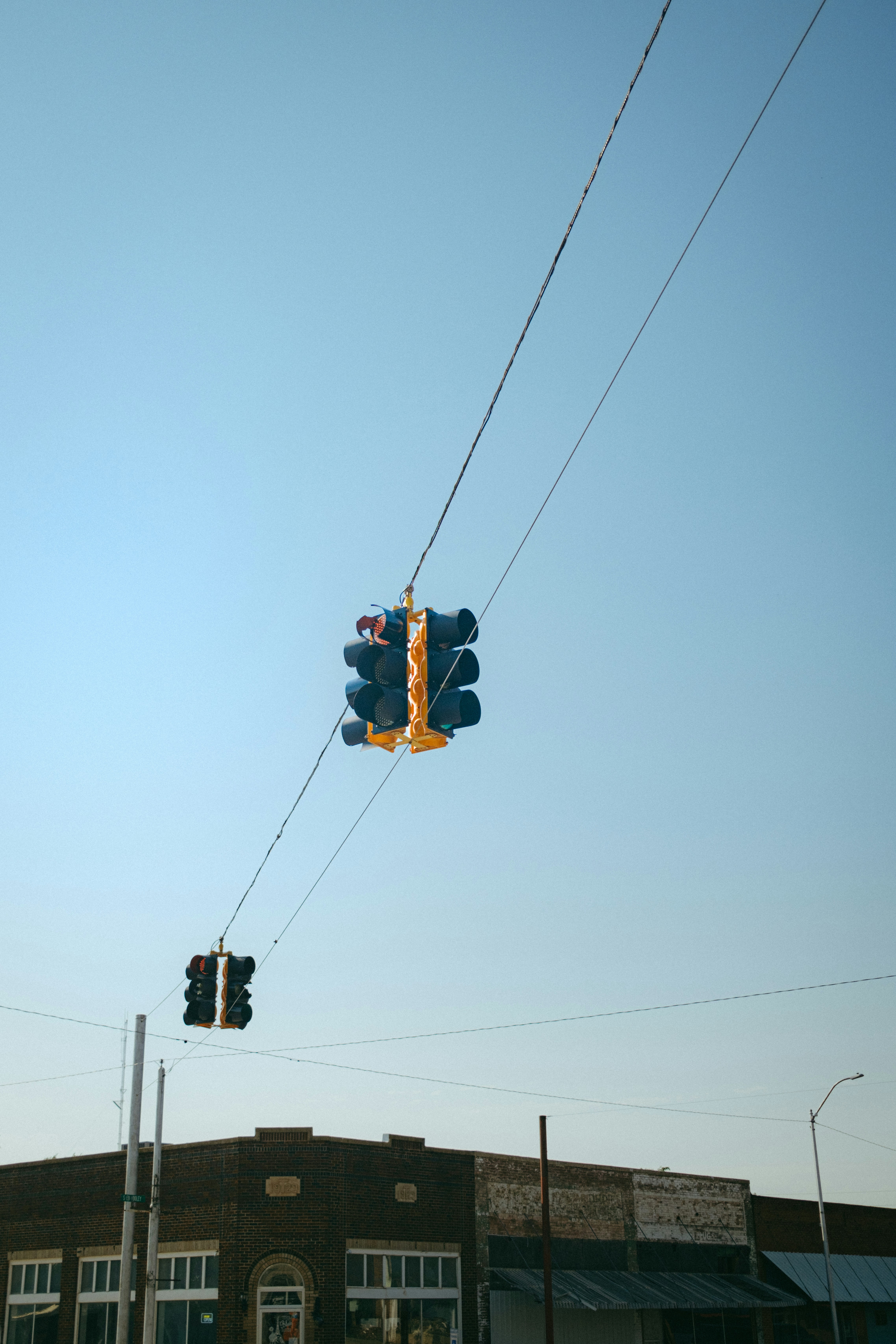 Orange Support Straps Carried by Power Cables Above a Quiet Urban Street