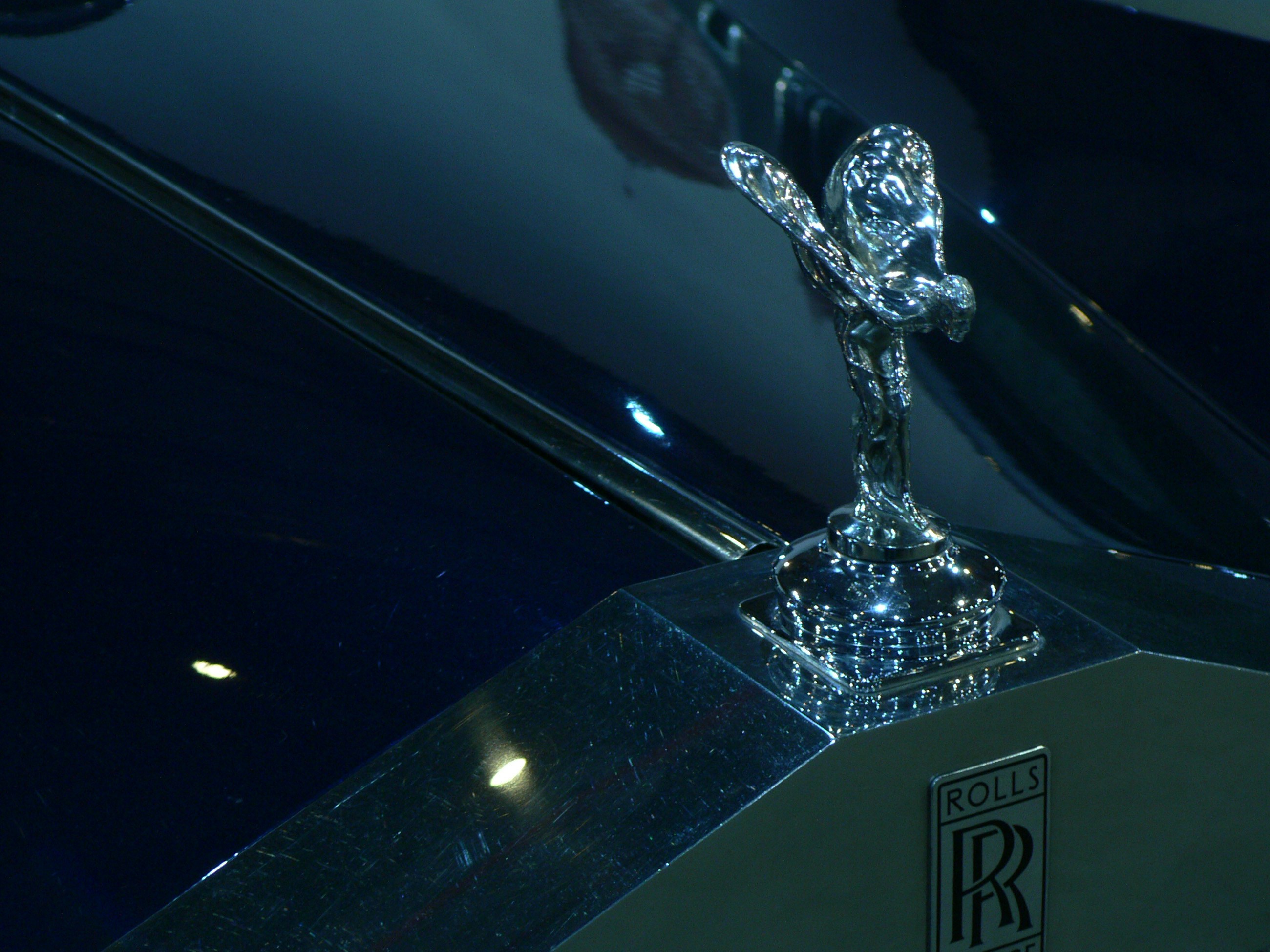 Iconic Spirit: The Rolls-Royce Hood Ornament Gracing a Midnight Badge
