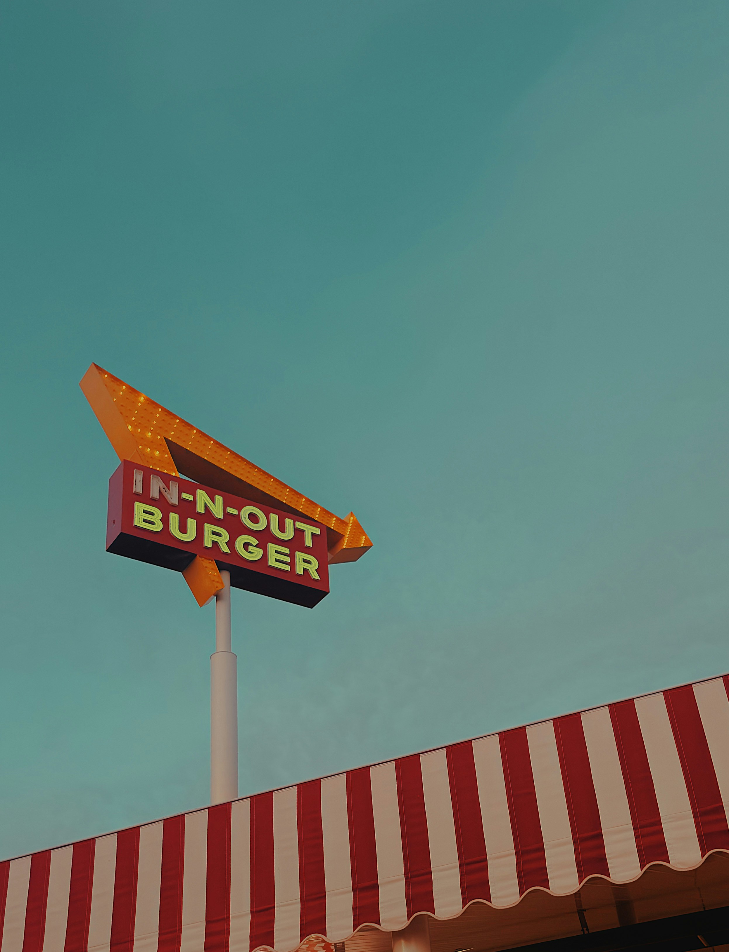 Neon Burger Sign Rises Over Striped Canopy