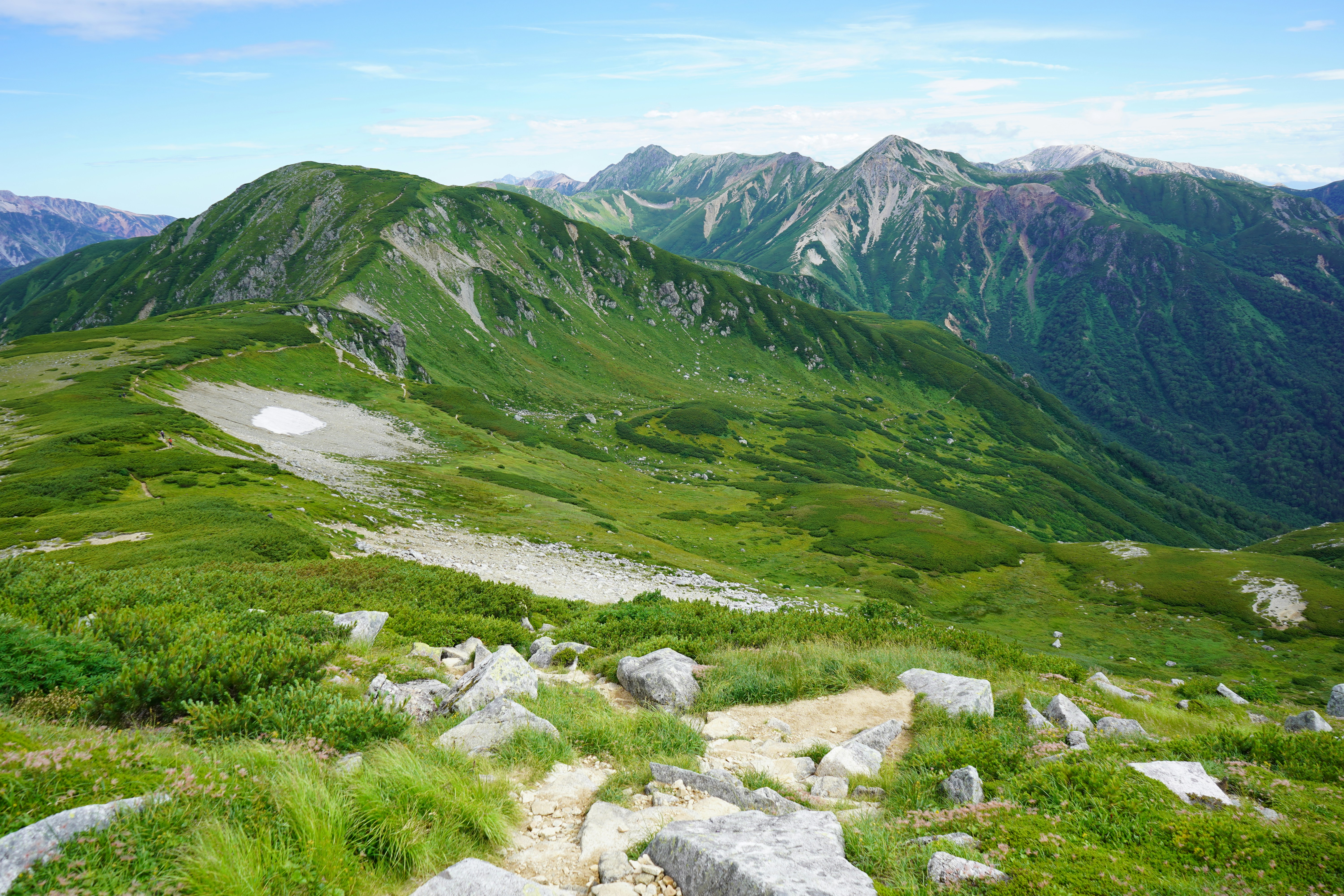  alpine saddle: sunlit ridges and open meadow under rolling peaks 
