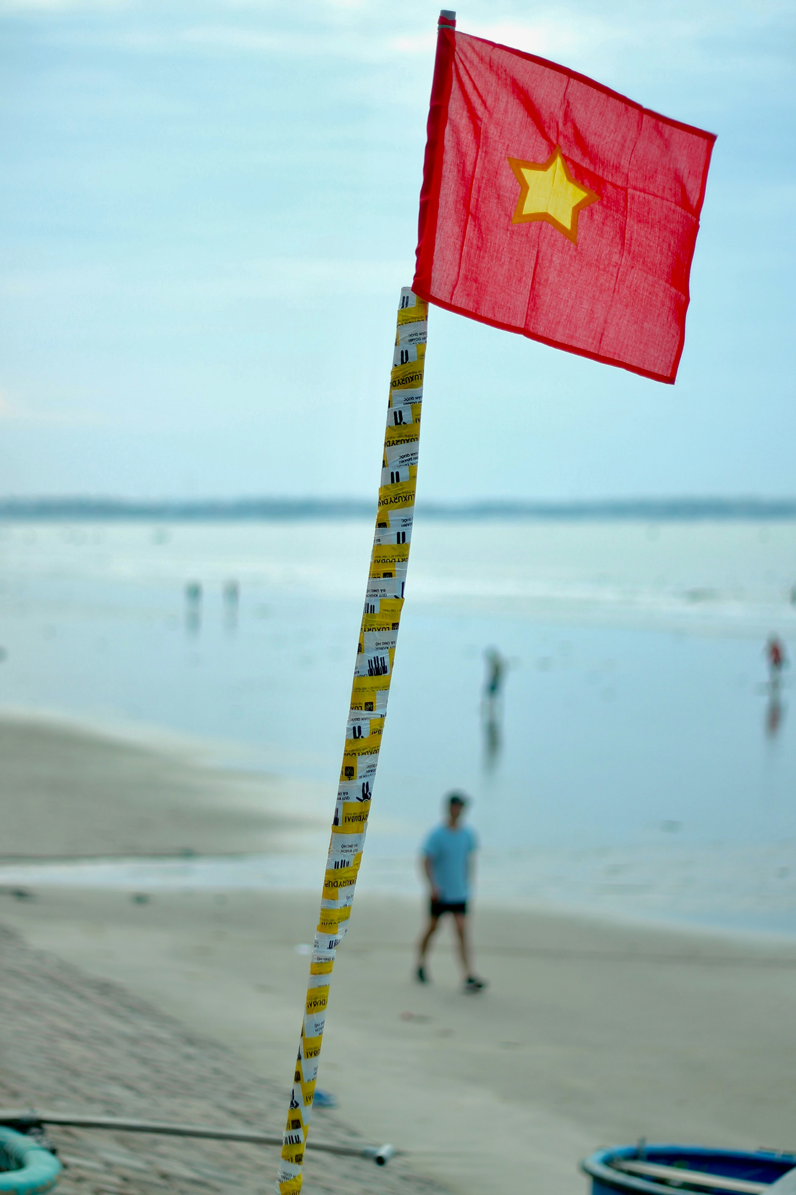 Red Flag on the Quiet Shore: A Lone Beach Marker with a Yellow Star